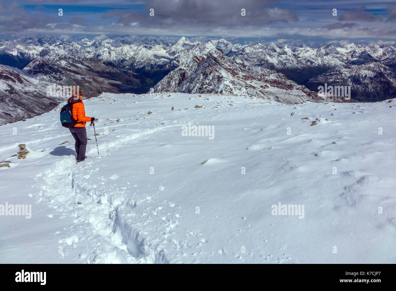 Female mountain walker on snow wearing orange duvet jacket Stock Photo ...