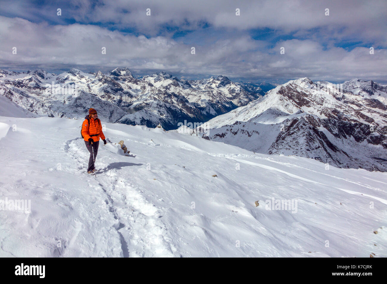Female mountain walker on snow wearing orange duvet jacket Stock Photo ...