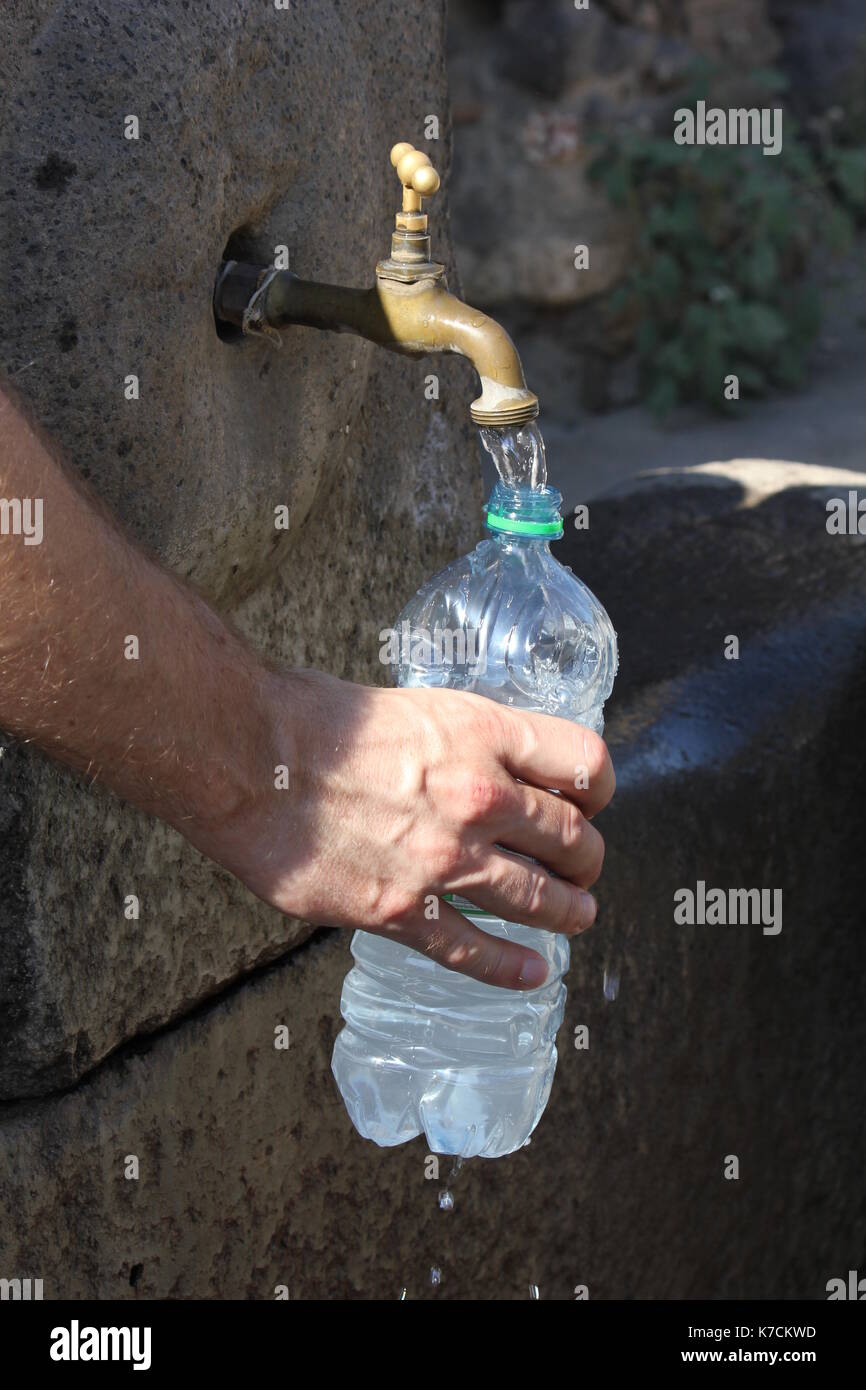 Detail of an arm while filling water in a plastic bottle at the ...
