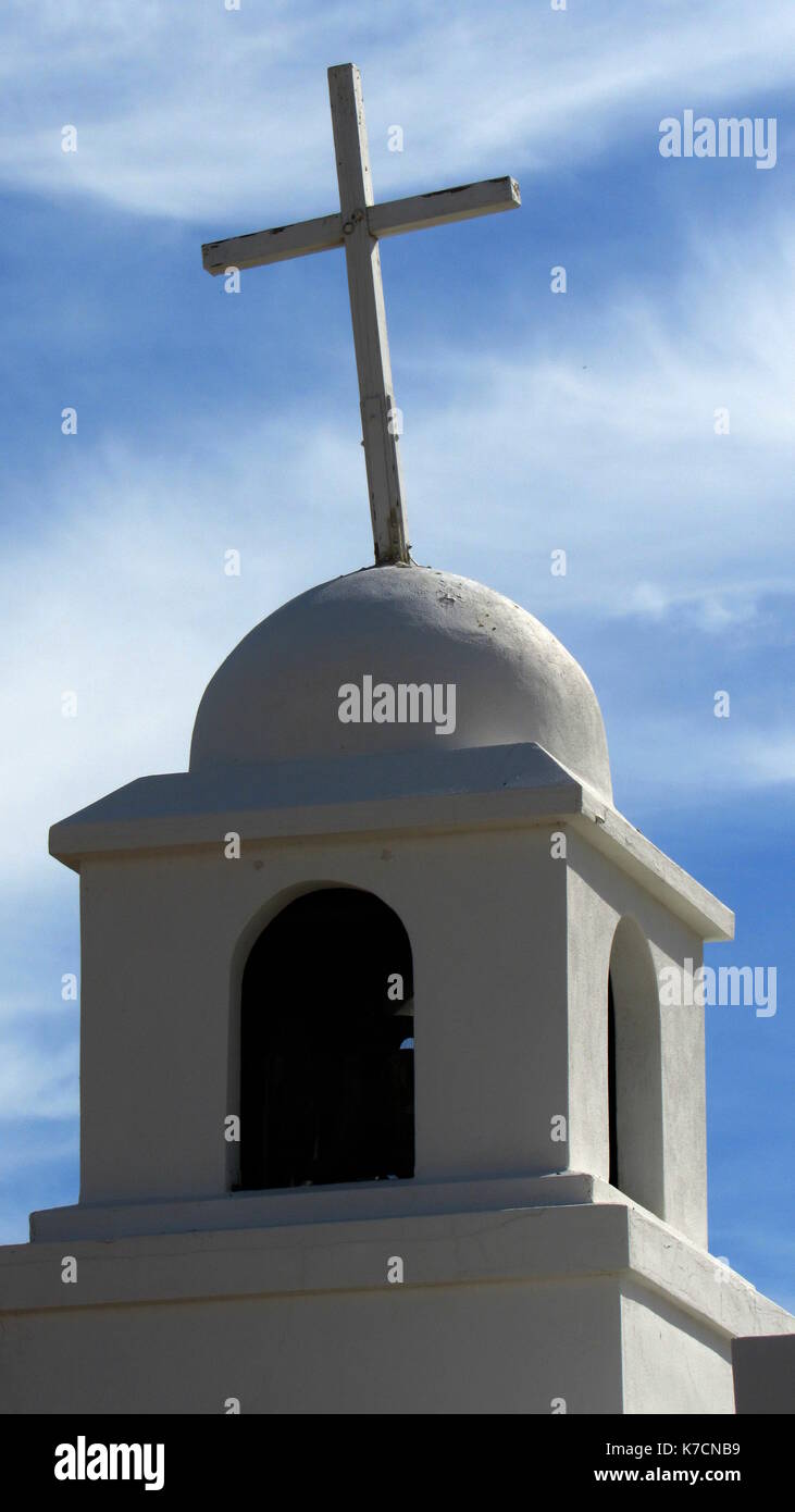 White catholic church with crooked white wooden cross and bell in ...