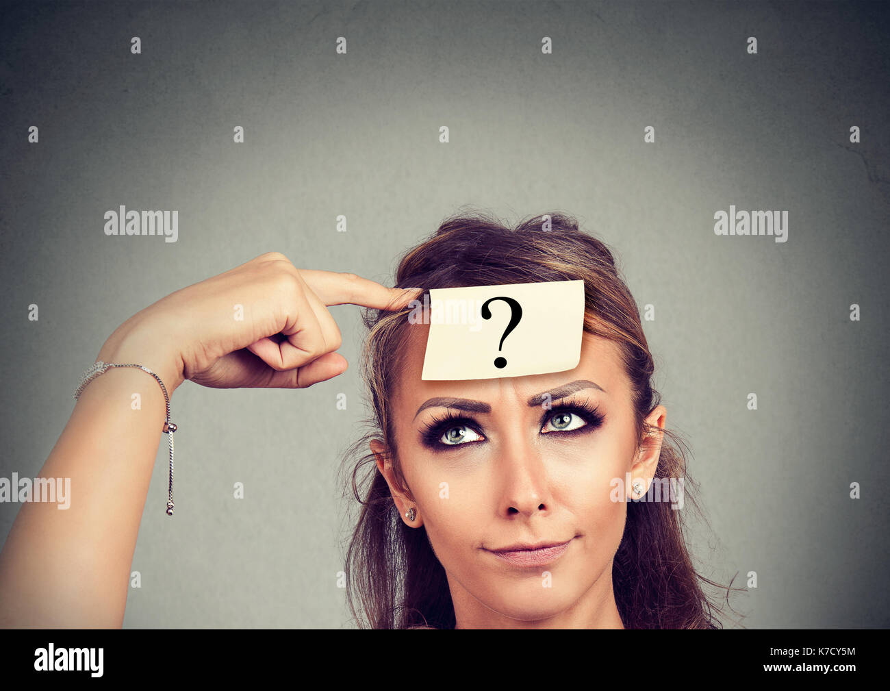 Thinking perplexed woman with question mark isolated on gray wall ...