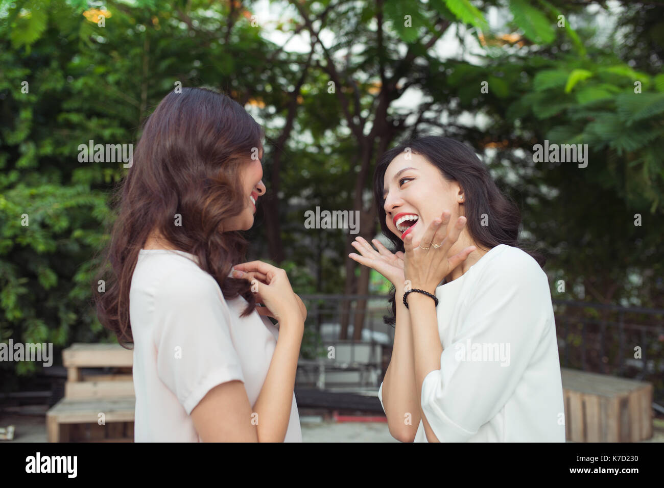 Happy young women friends well-dressed smiling while standing together ...