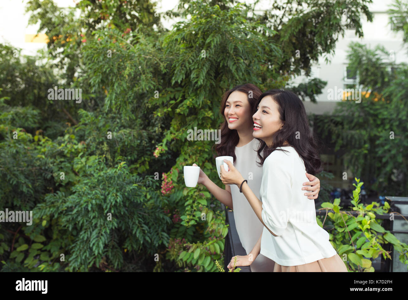 Happy young women friends well-dressed smiling while standing together ...