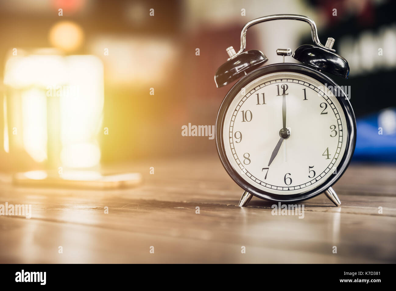 7 o'clock time retro clock on wood table with sun light background ...
