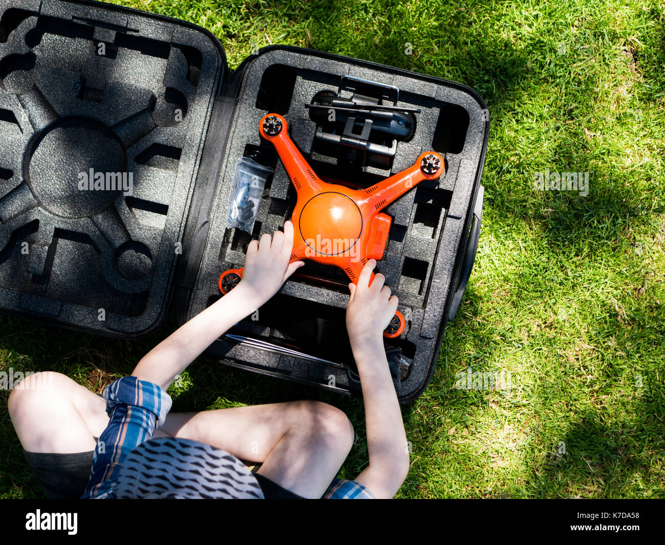 Overhead view of boy removing quadcopter from container while sitting ...