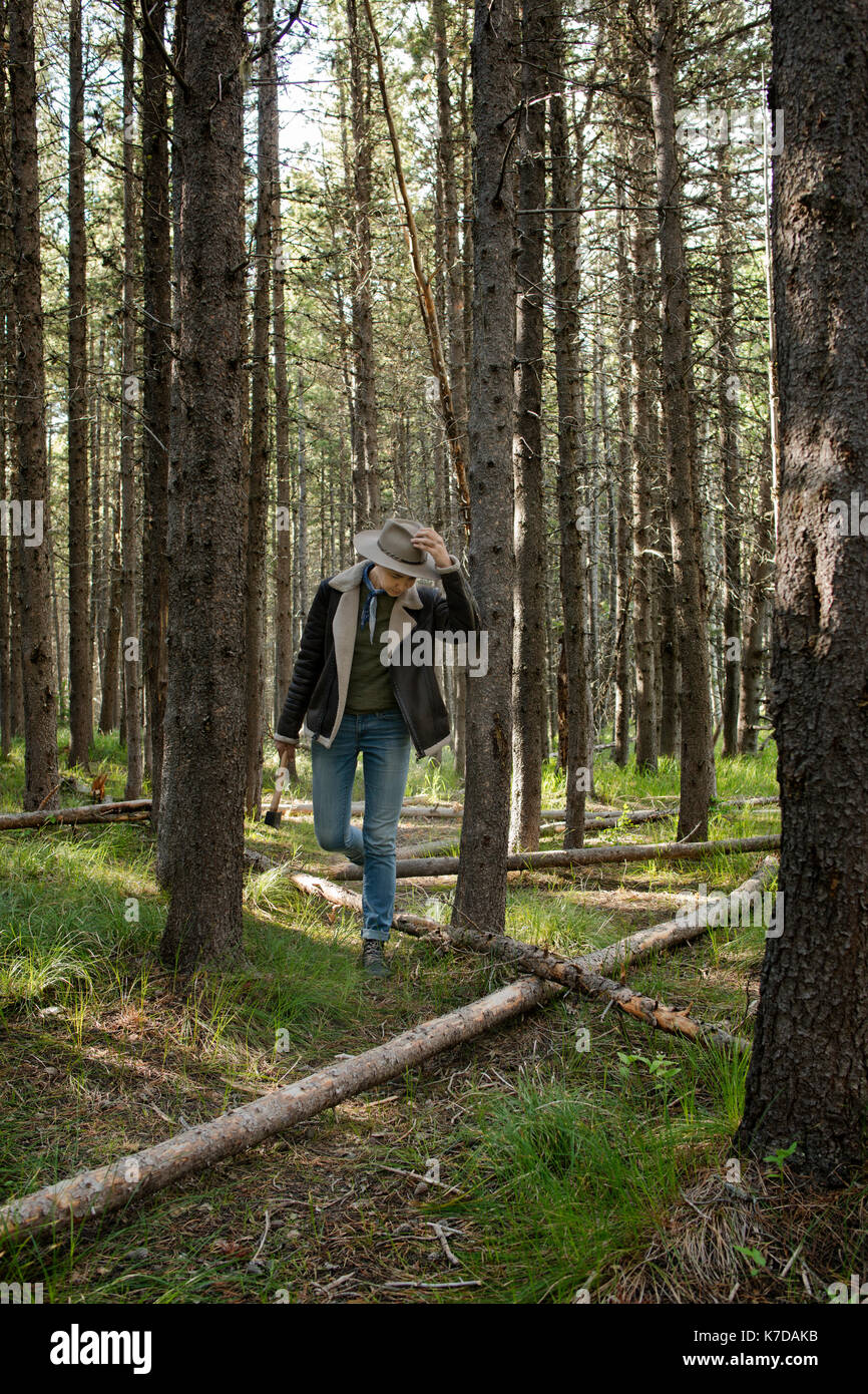 Female hiker walking amidst forest while holding axe Stock Photo - Alamy