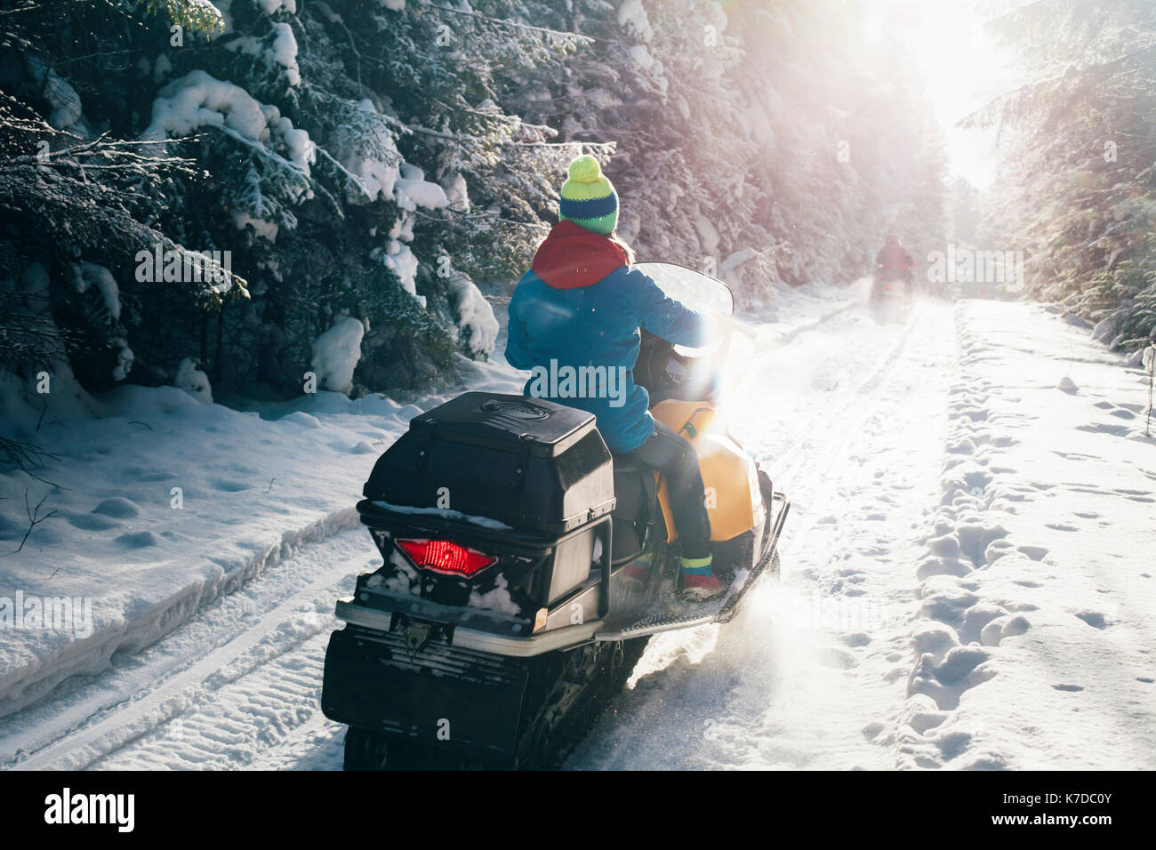 Rear view of woman riding snowmobile on snow covered field Stock Photo ...