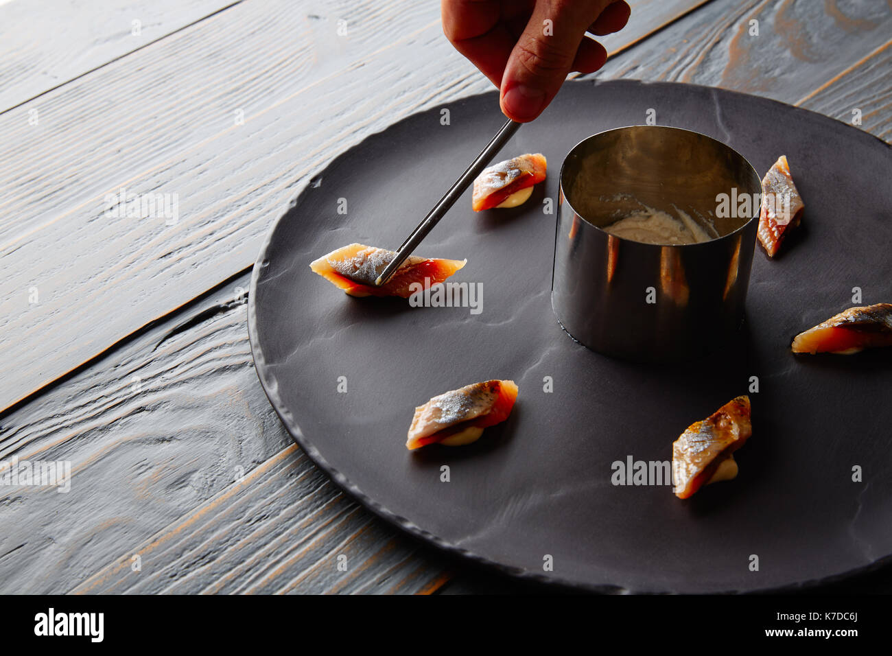 Bota sardine preparation with chef hand on black slate dish Stock Photo ...