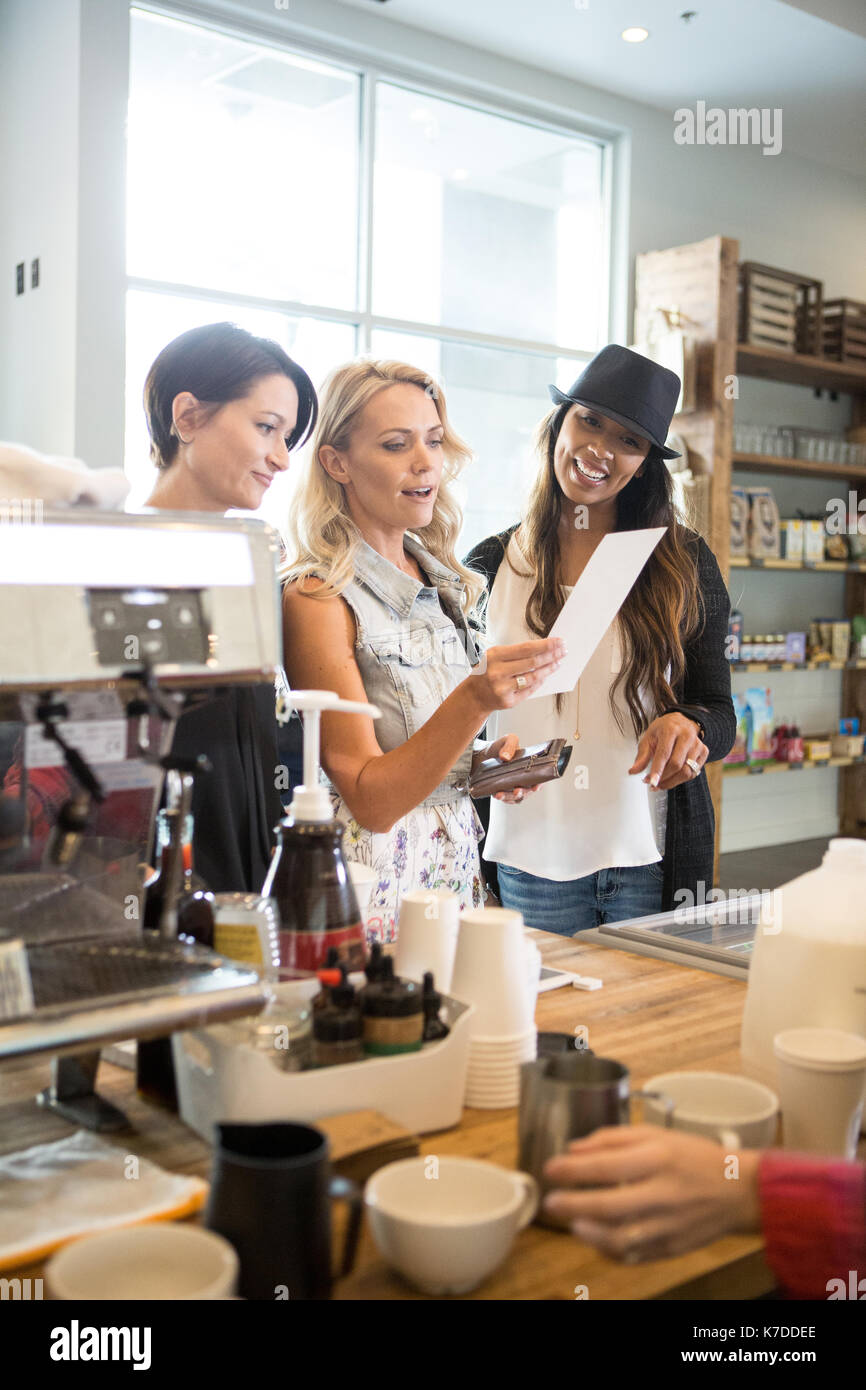 Happy female friends reading menu while standing at counter in ...