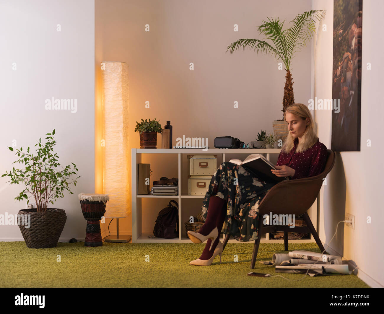 Woman reading book while sitting on chair at home Stock Photo - Alamy