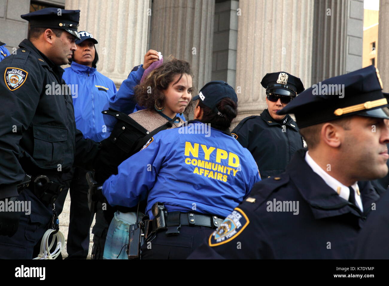 NYPD officers arrest a young woman as she attempts to stand on the ...