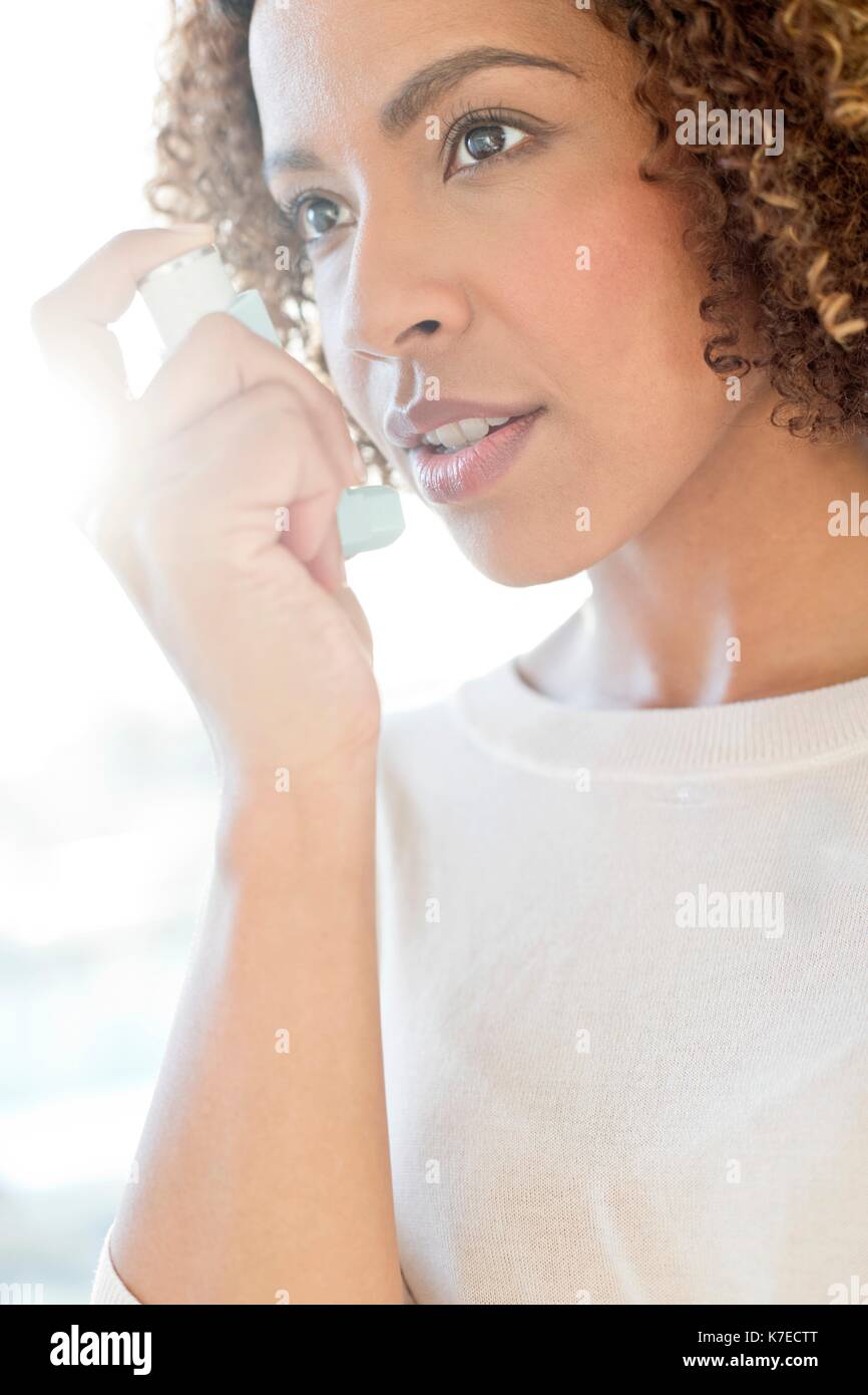 Mid adult woman using inhaler Stock Photo - Alamy