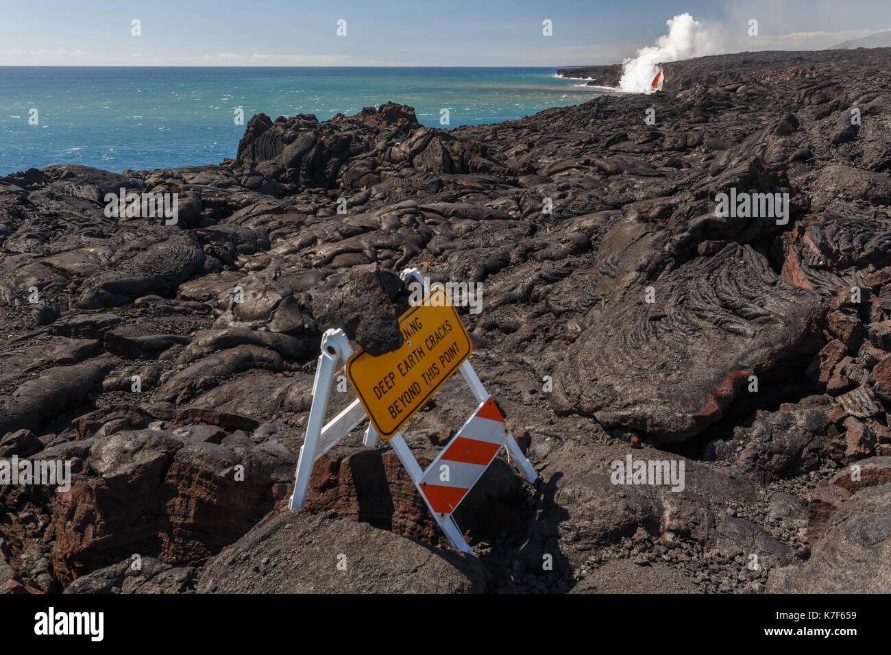 Caution sign on lava beds. Bright red lava flow of volcano in Hawaii on ...