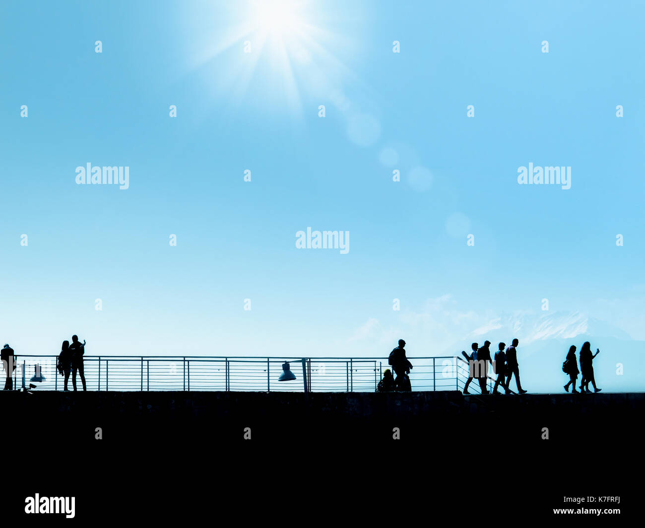 silhouetted people walking over sunny blue sky Stock Photo - Alamy