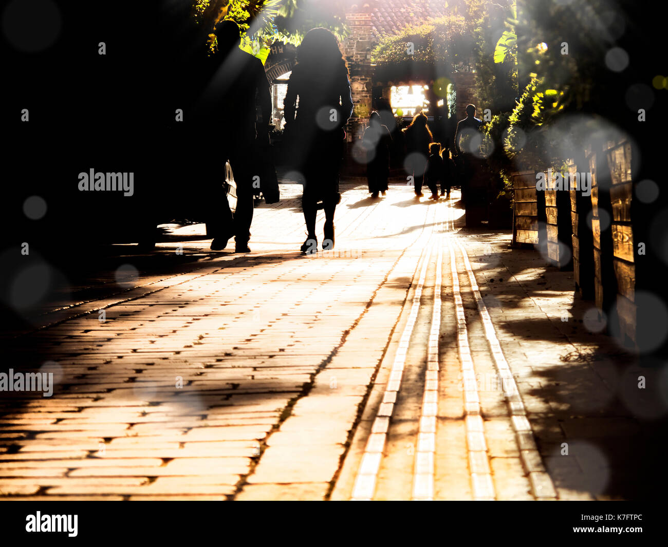 silhouetted people walking on street and sunbeam Stock Photo - Alamy