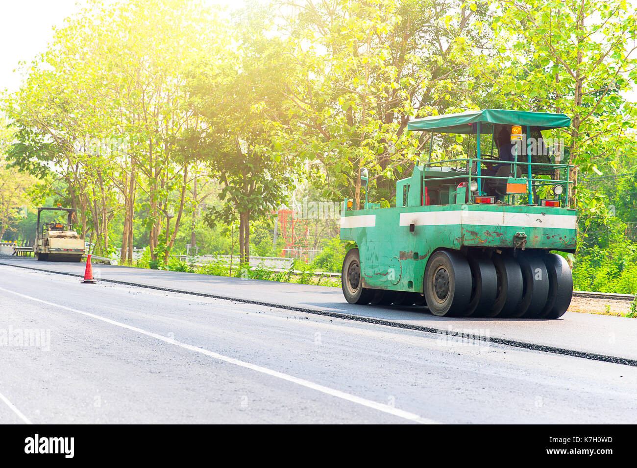 asphalt road construction with machine and steamroller truck at freeway ...