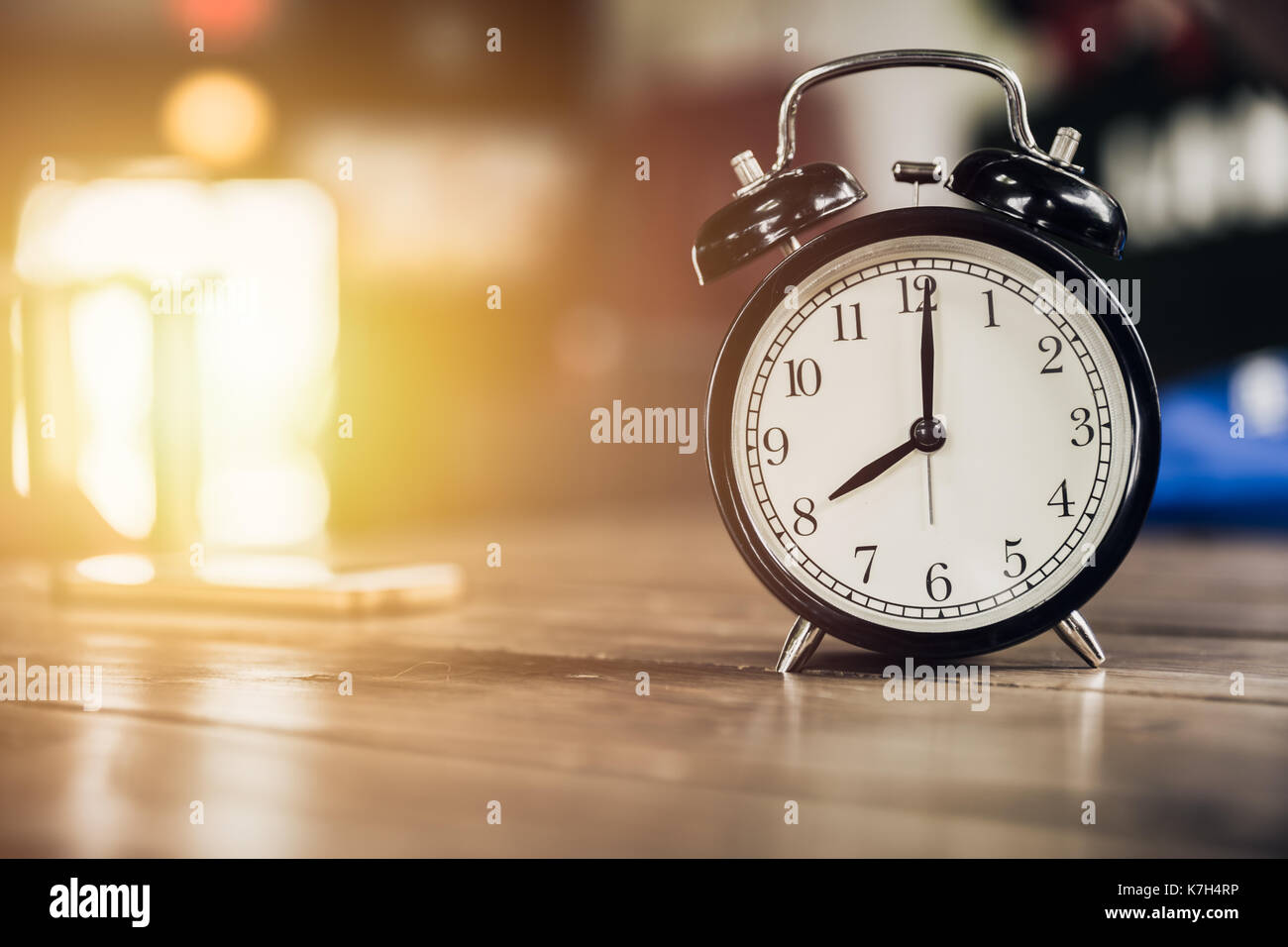 8 o'clock time retro clock on wood table with sun light background ...