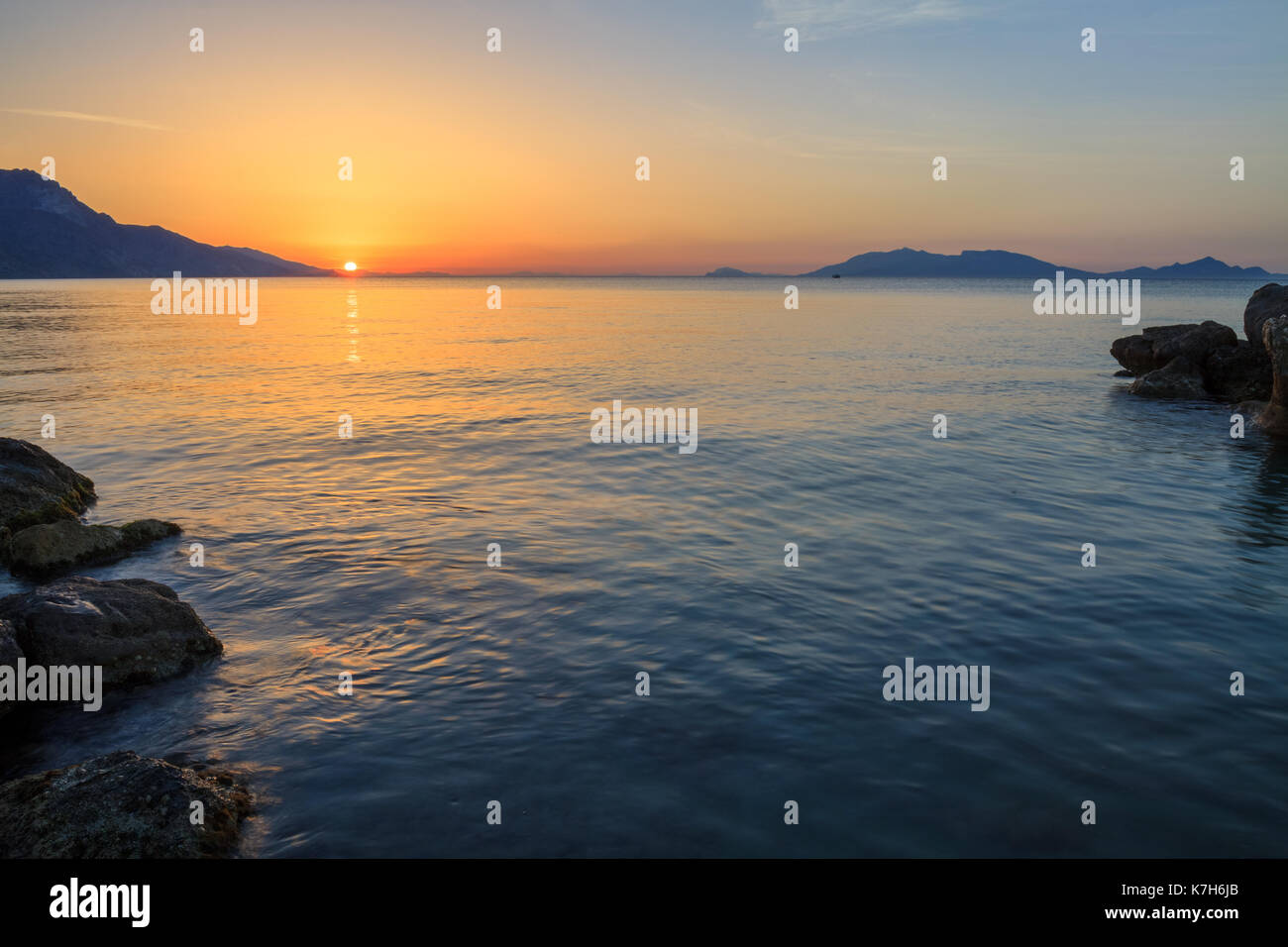 Beautiful sunrise landscape with sea, rock and mountains Stock Photo ...