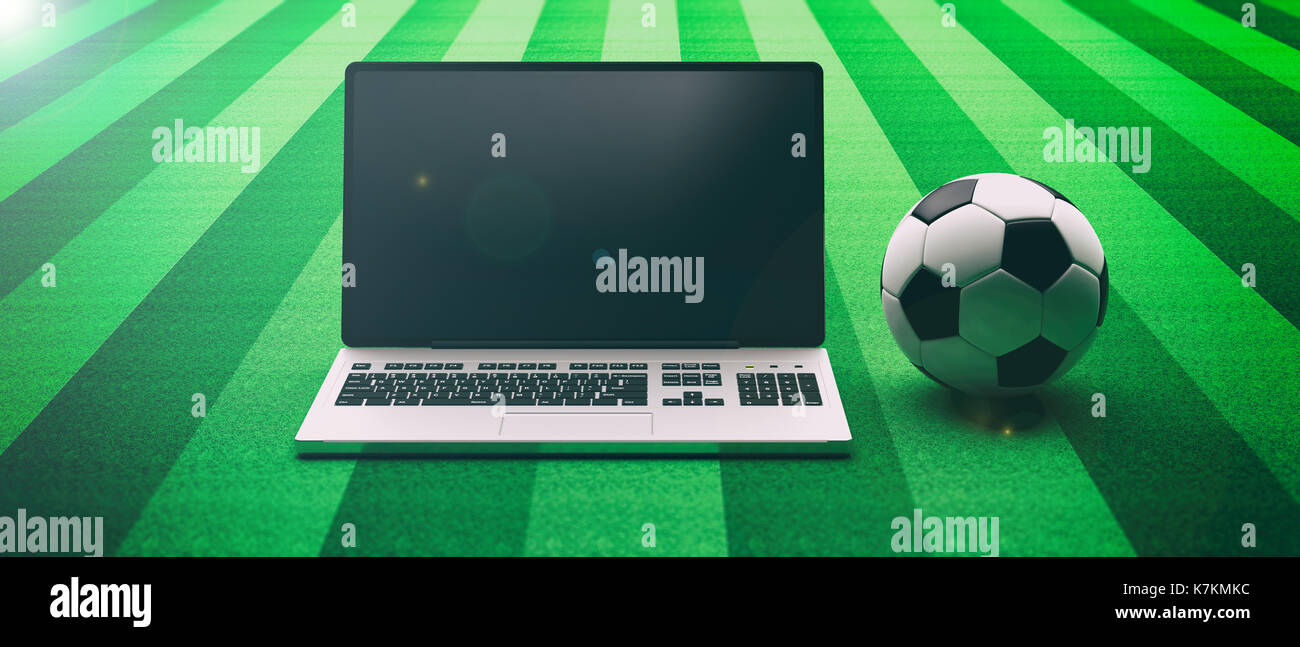 Soccer football ball and a computer on an illumunated field grass ...