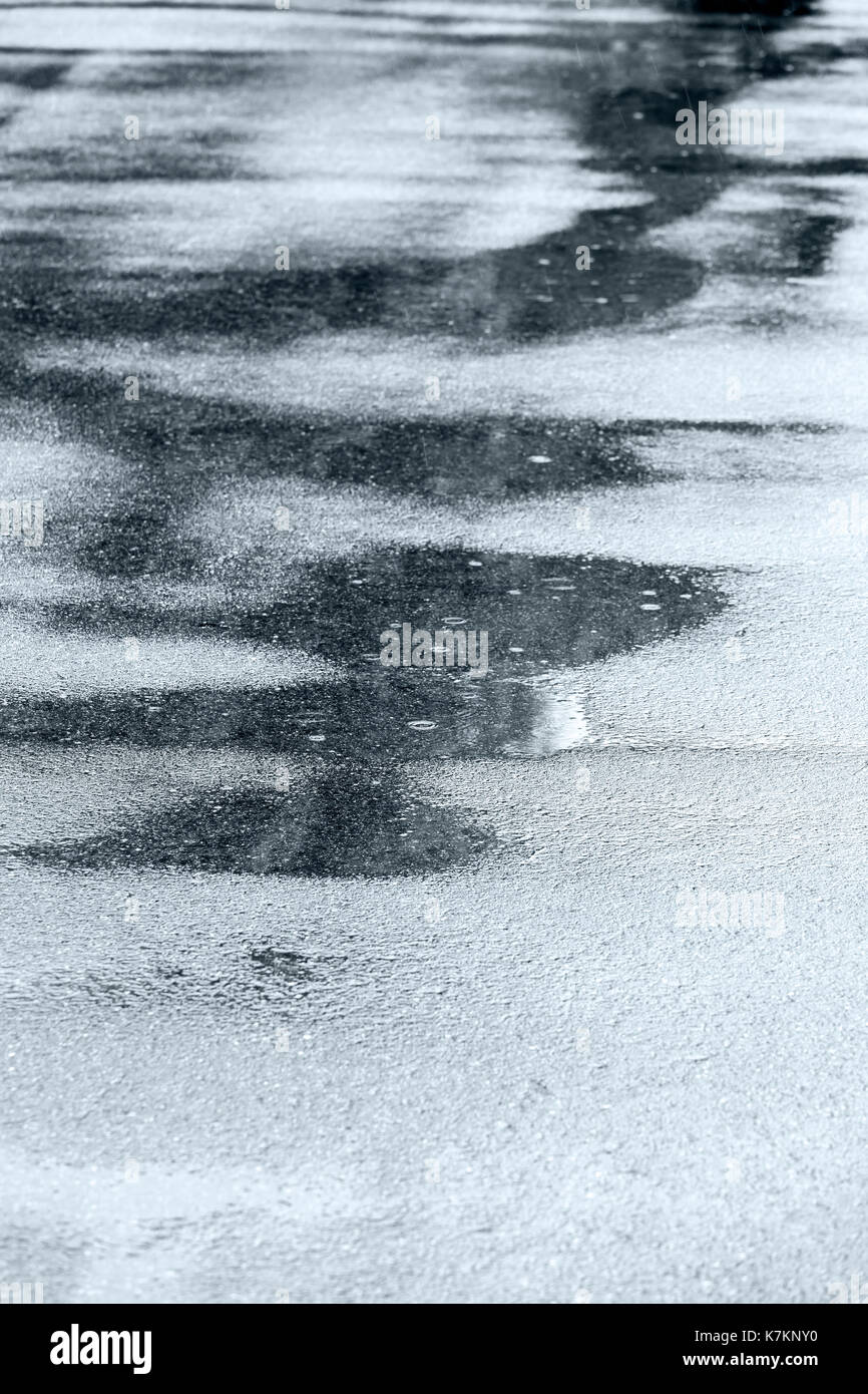 rain falling on asphalt road creating water puddles on rainy day Stock ...