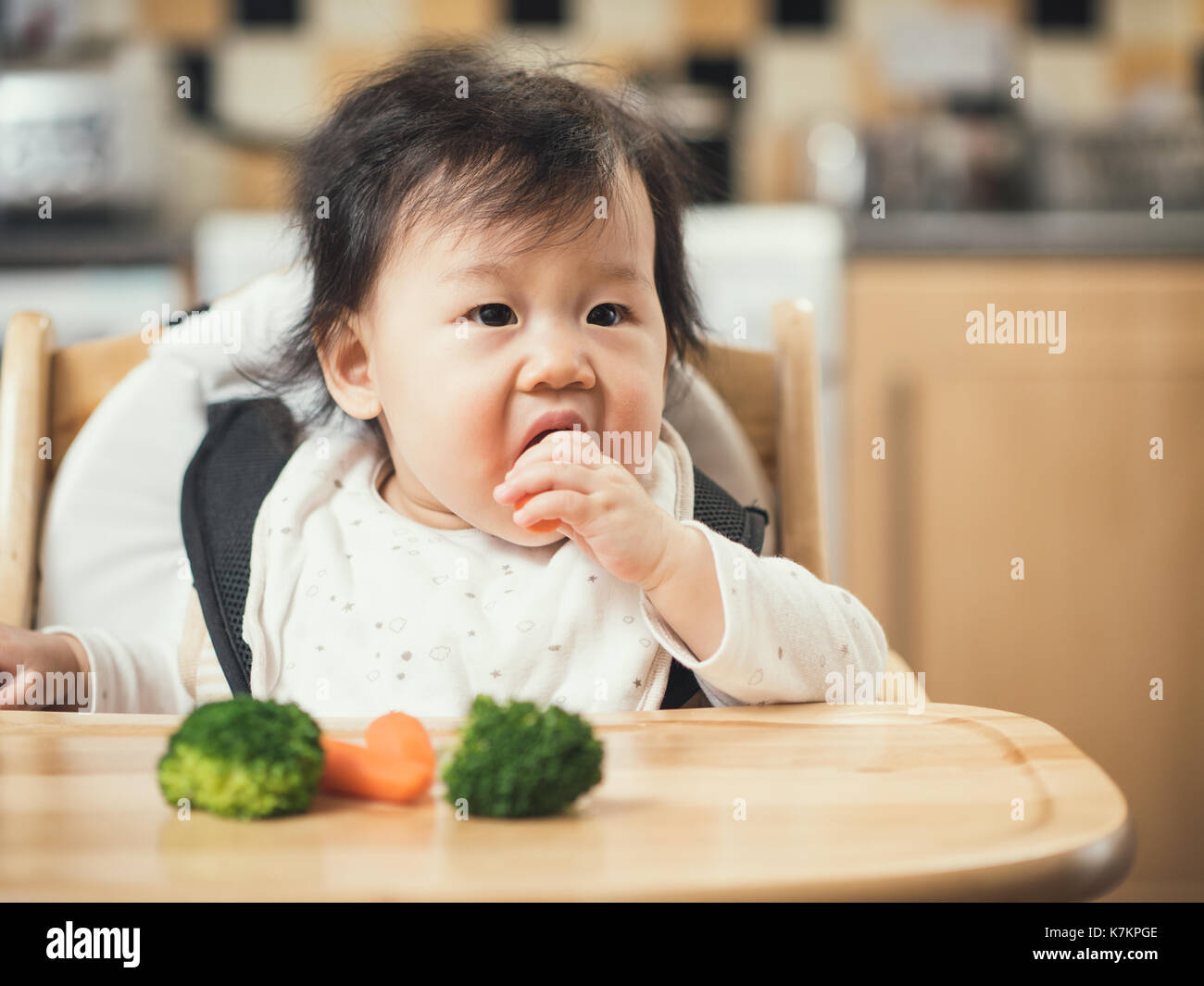 baby girl eating broccoli,carrot vegetable i first time at home Stock ...