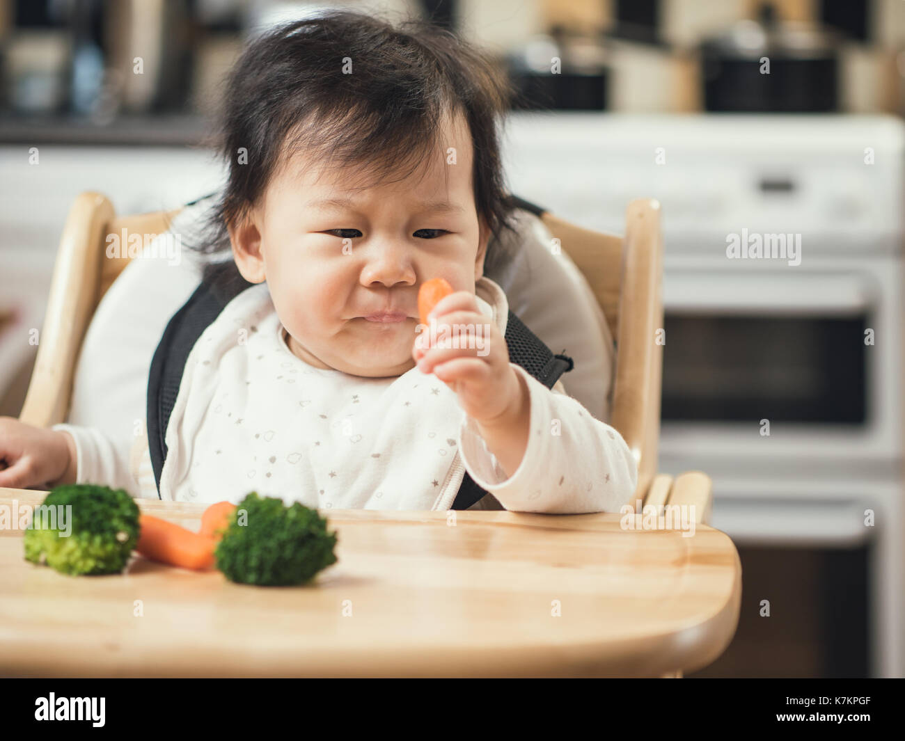baby girl eating broccoli,carrot vegetable i first time at home Stock ...