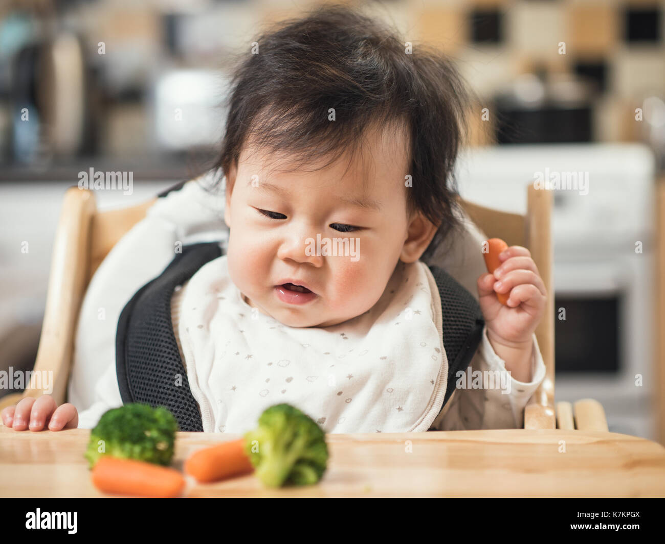 baby girl eating broccoli,carrot vegetable i first time at home Stock ...