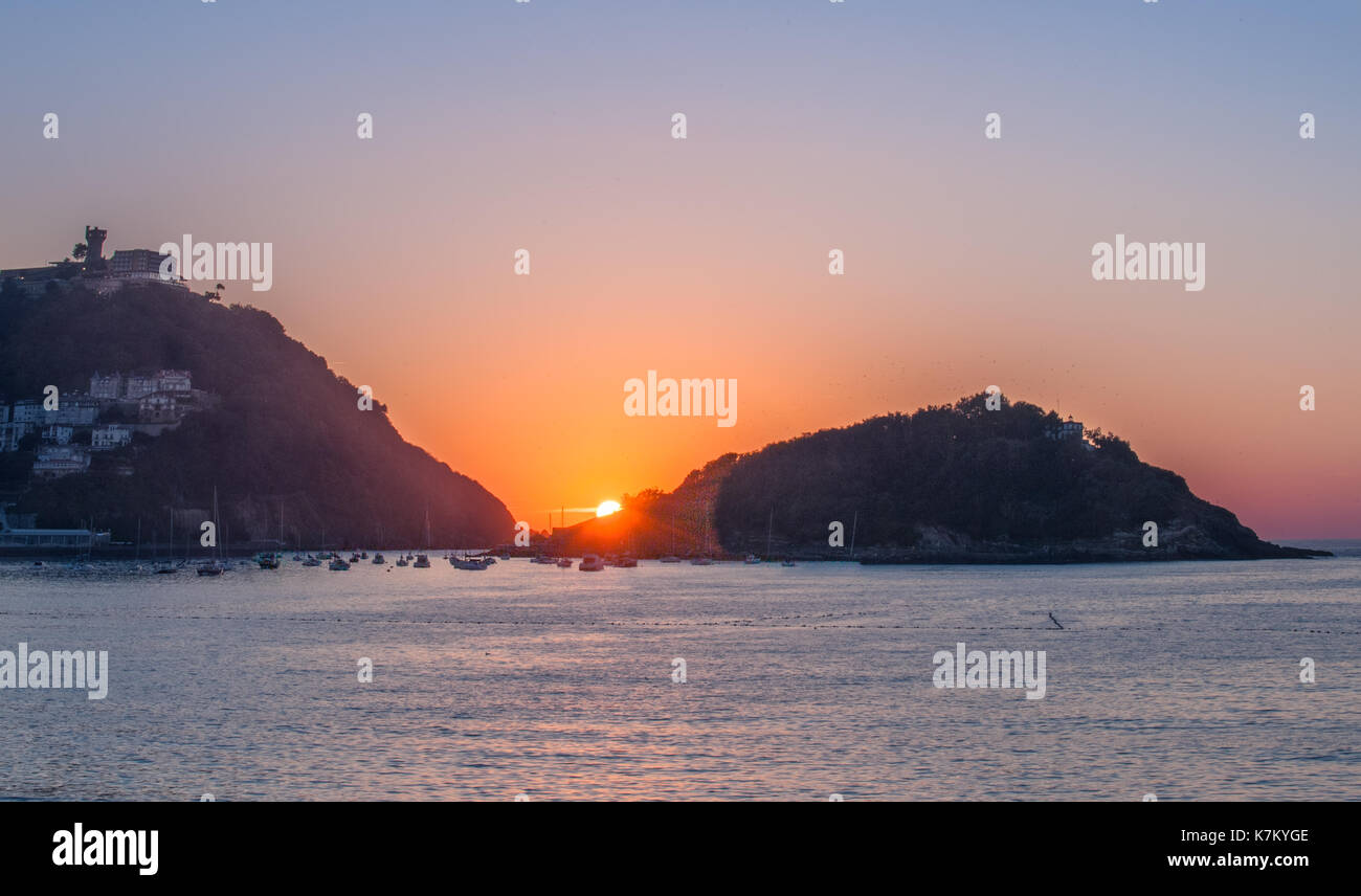 Scenic seaside sunset between two mountains with boats silhouettes ...