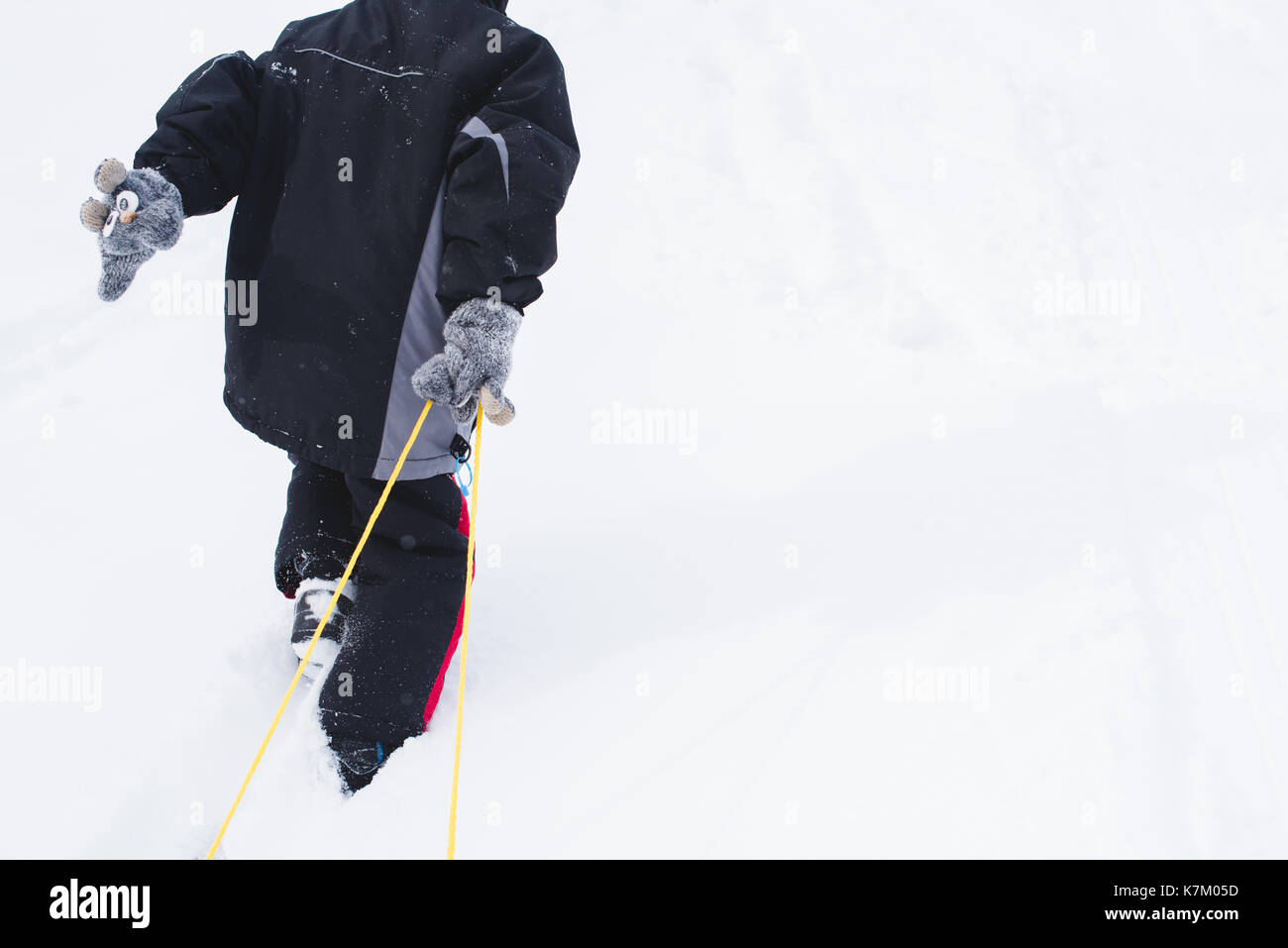 Young boy pulling a sled up a snow covered hill in the winter Stock ...