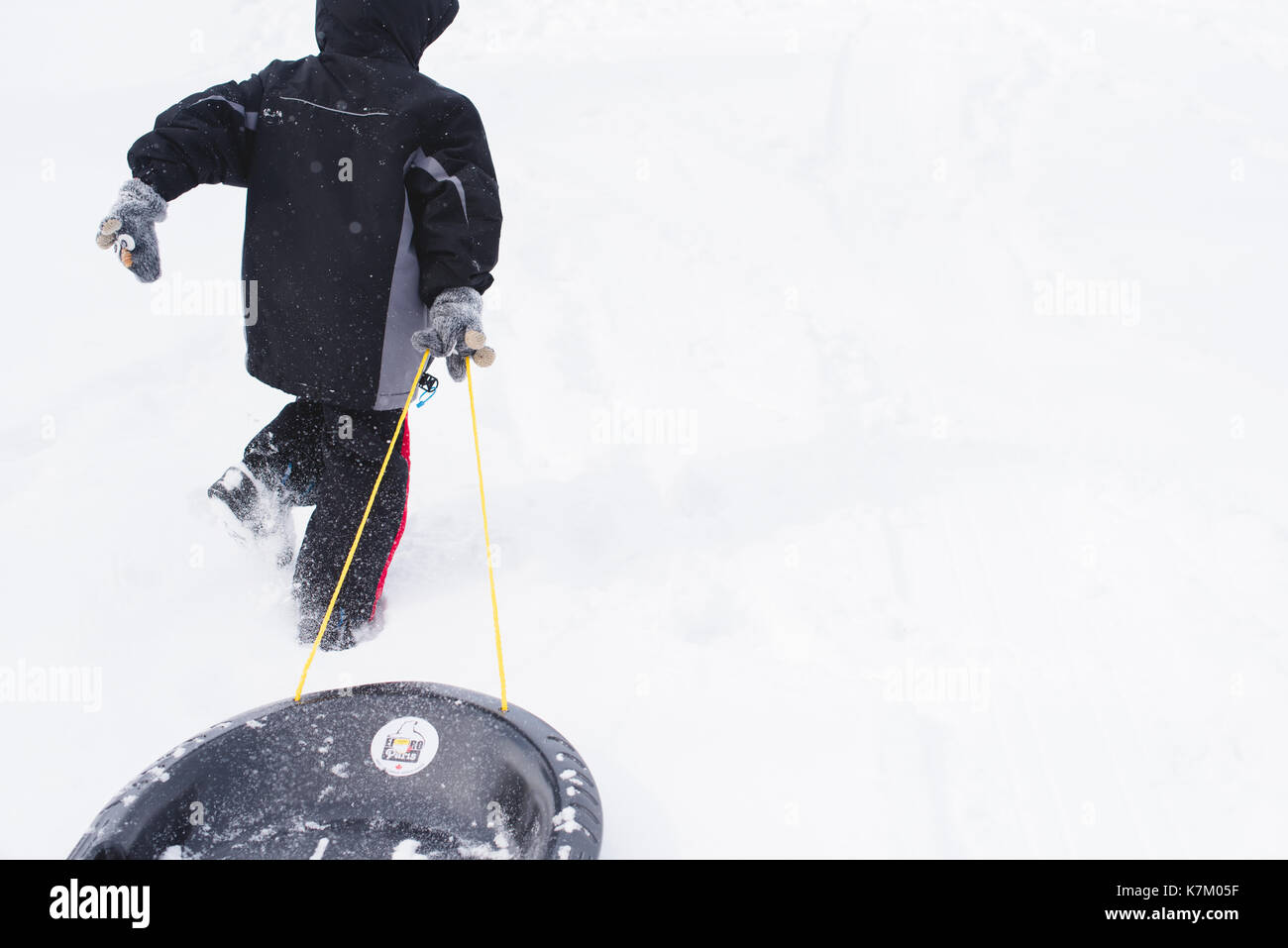 Young boy pulling a sled up a snow covered hill in the winter Stock ...