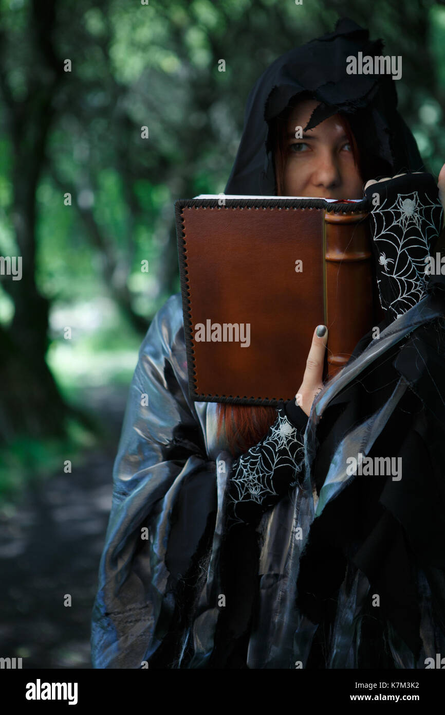 Picture of witch reading spell from book in mystical forest Stock Photo ...