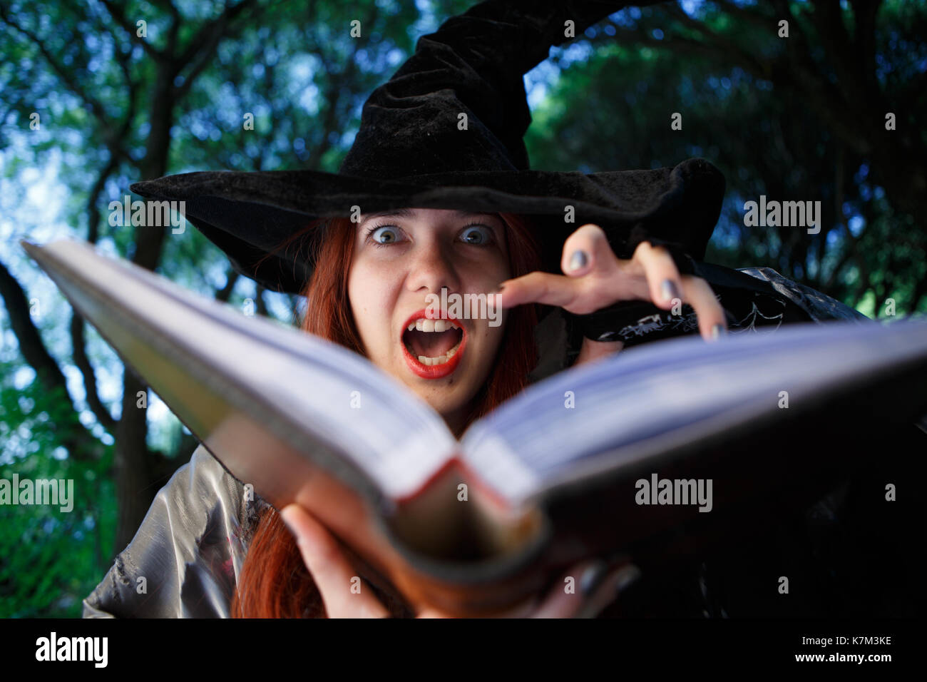 Close-up image of witch reading spell from book in evening forest Stock ...