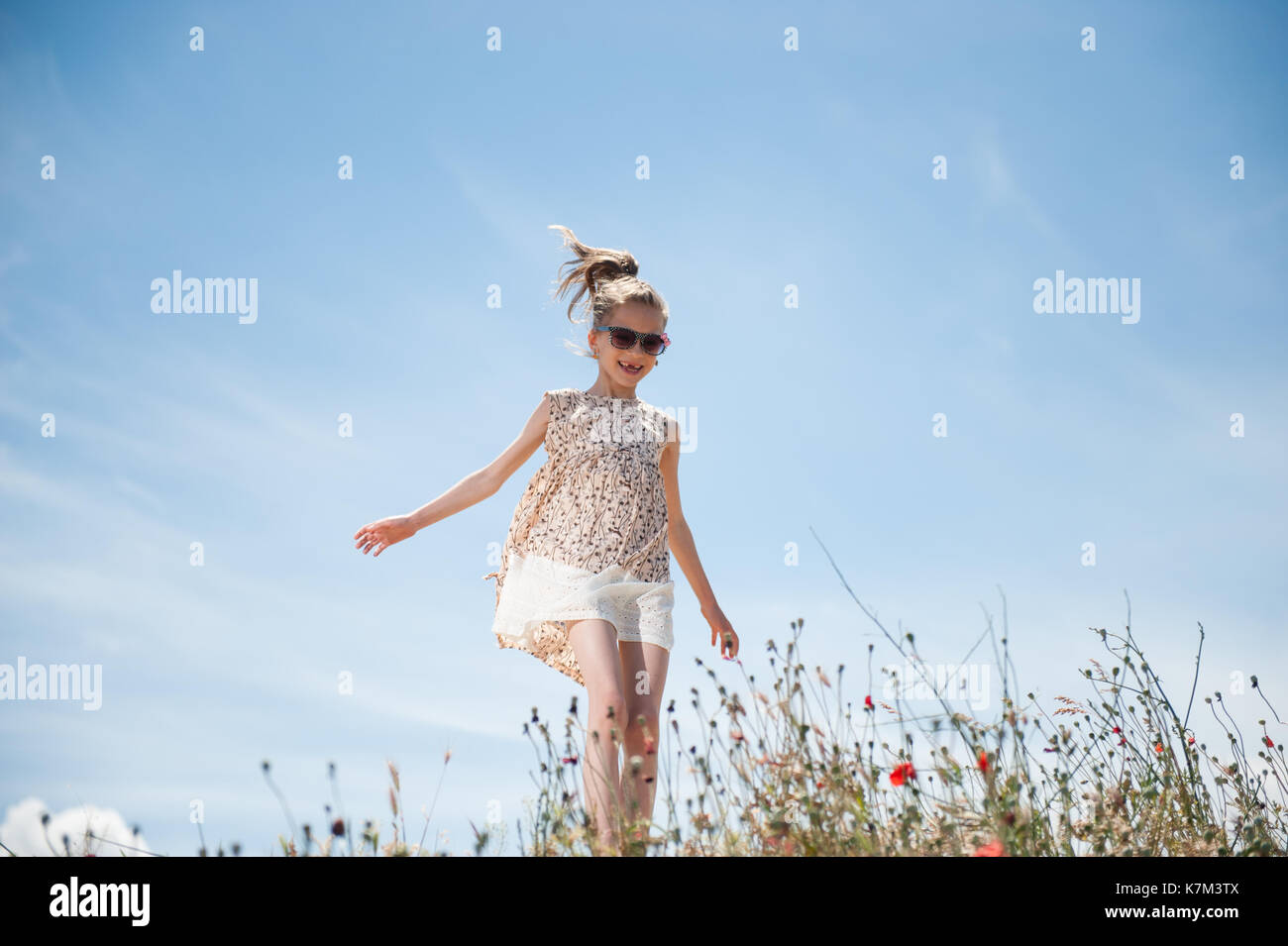 happy caucasian little girl refreshed by the wind walking among field ...