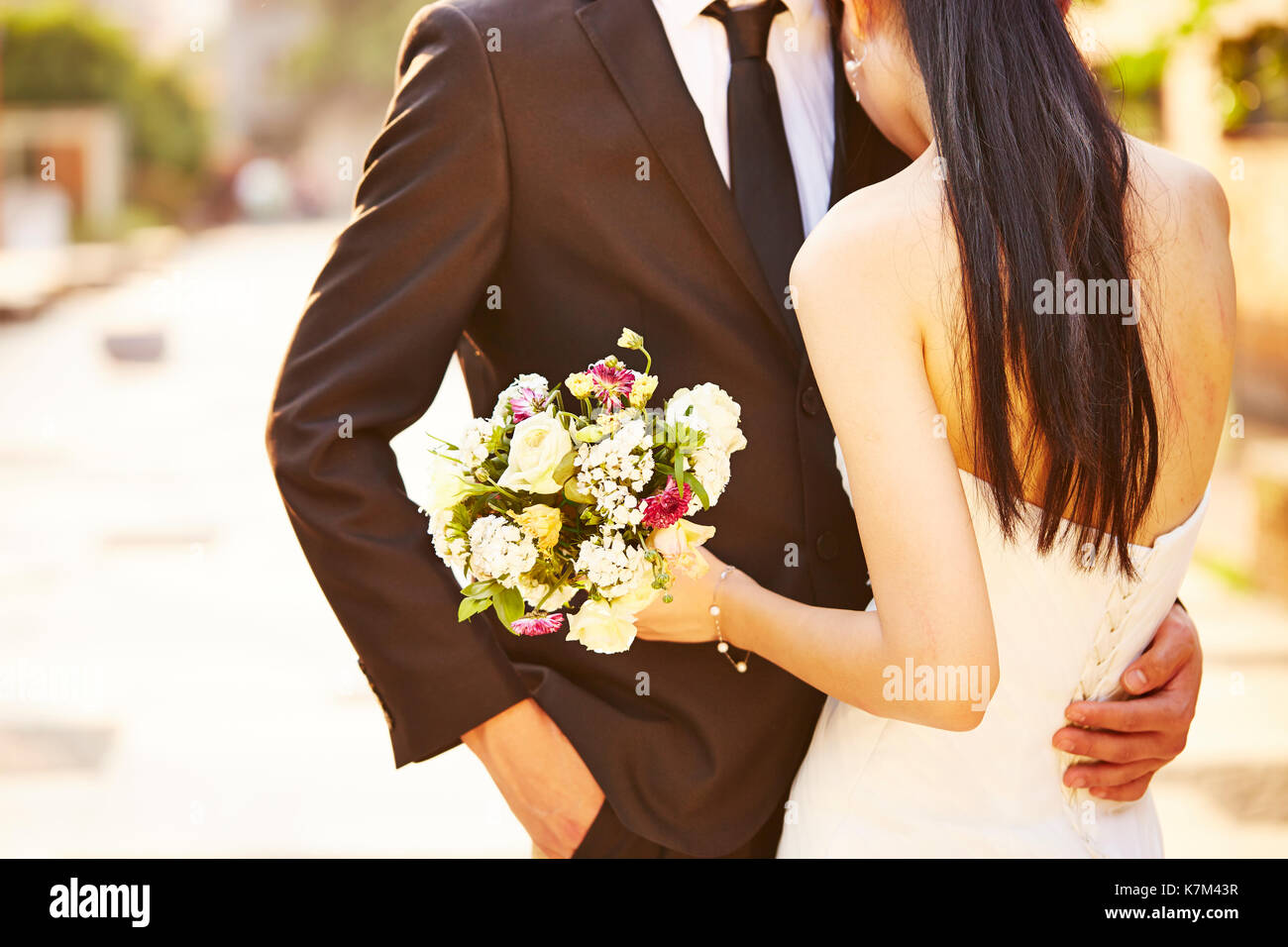 loving bride and groom with bouquet hugging each other at wedding day ...