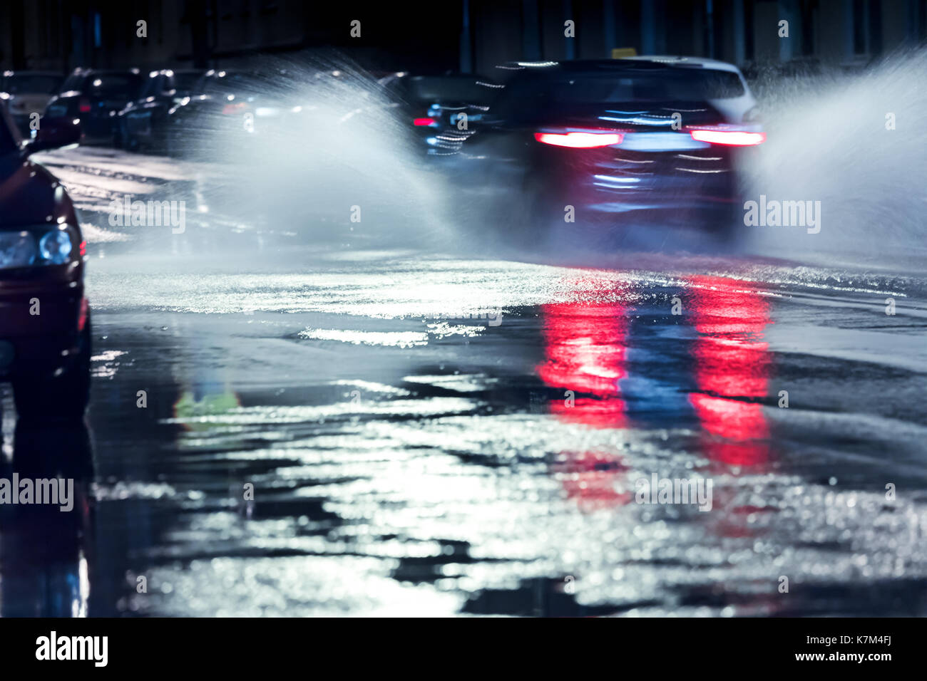 rainwater splashing from the wheels of car in motion with headlights ...