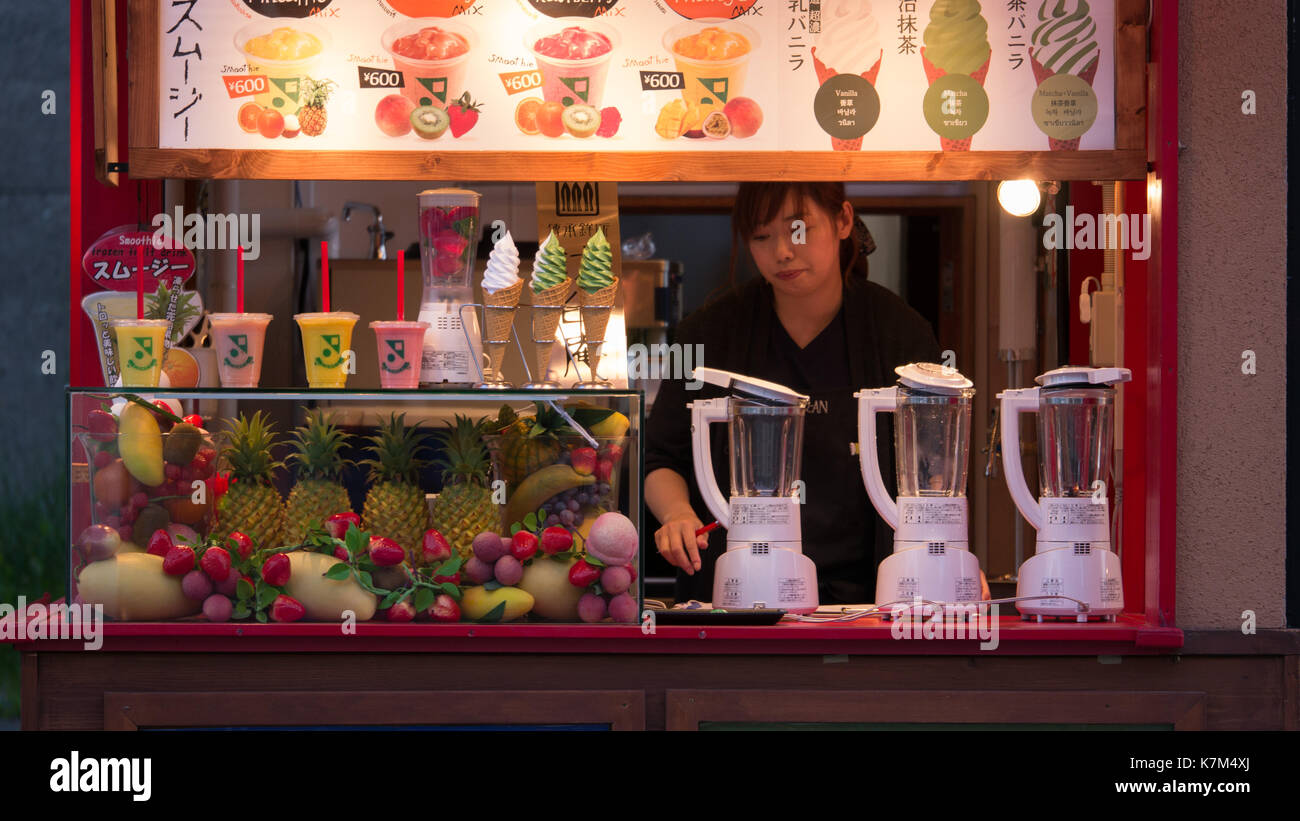 Japanese woman working behind counter of sidewalk ice cream and berry ...