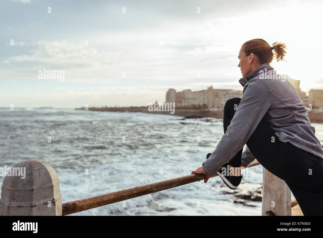 Healthy lifestyle. Woman in sportswear stretching her legs on railing ...