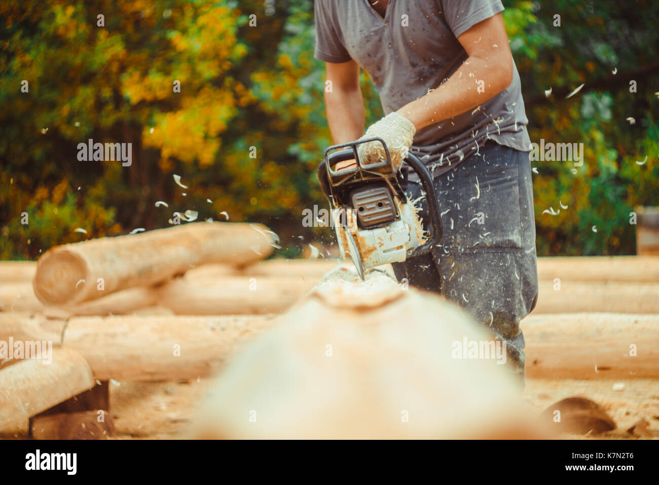 Man cutting piece of wood with chain saw Stock Photo - Alamy