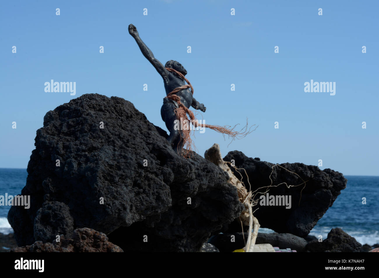 Photo of a Jesus figurine bound in rope and embedded in volcanic rock ...