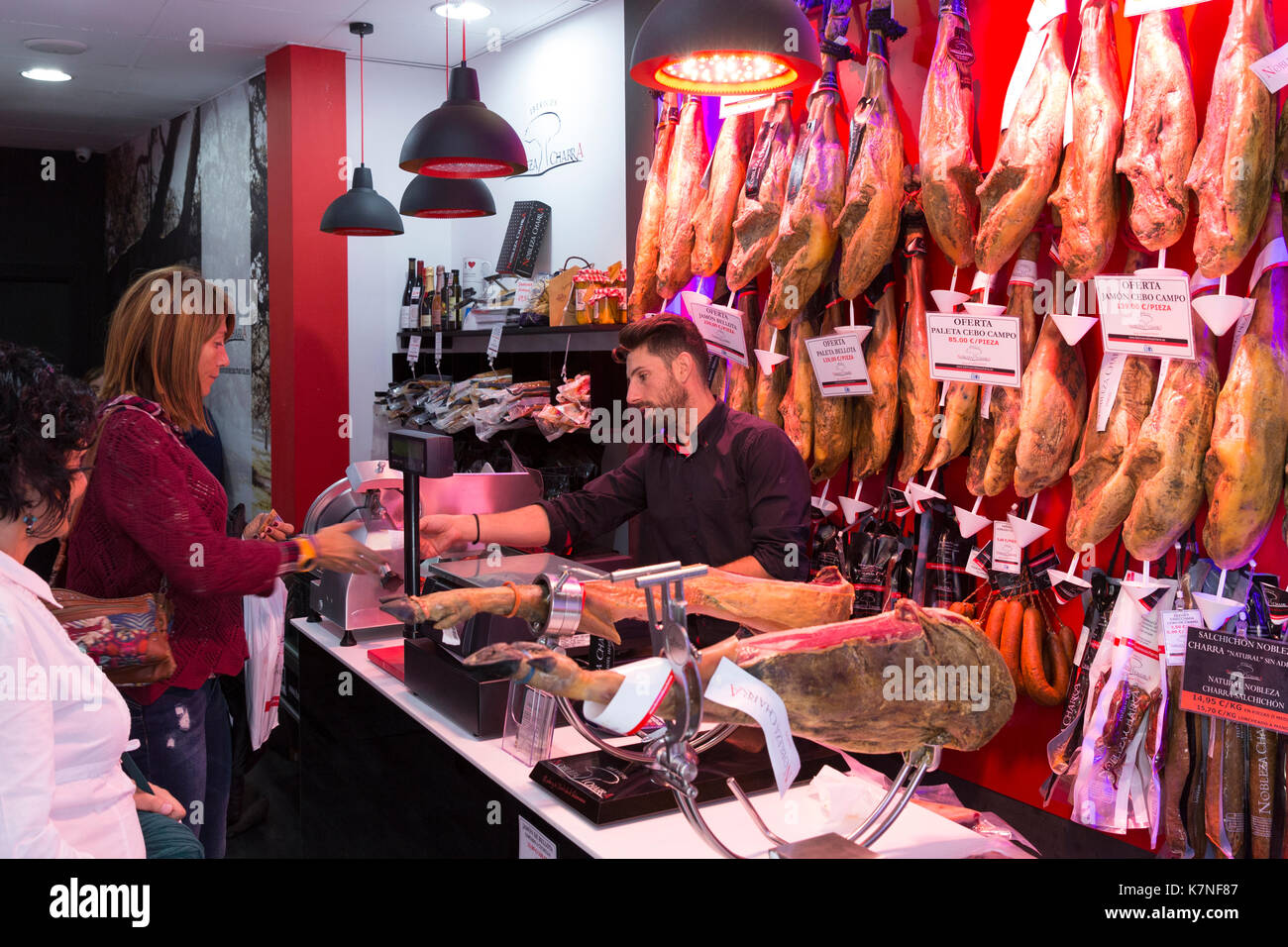 Women buying Iberico Jamon specialty Spanish ham in butcher shop in old ...