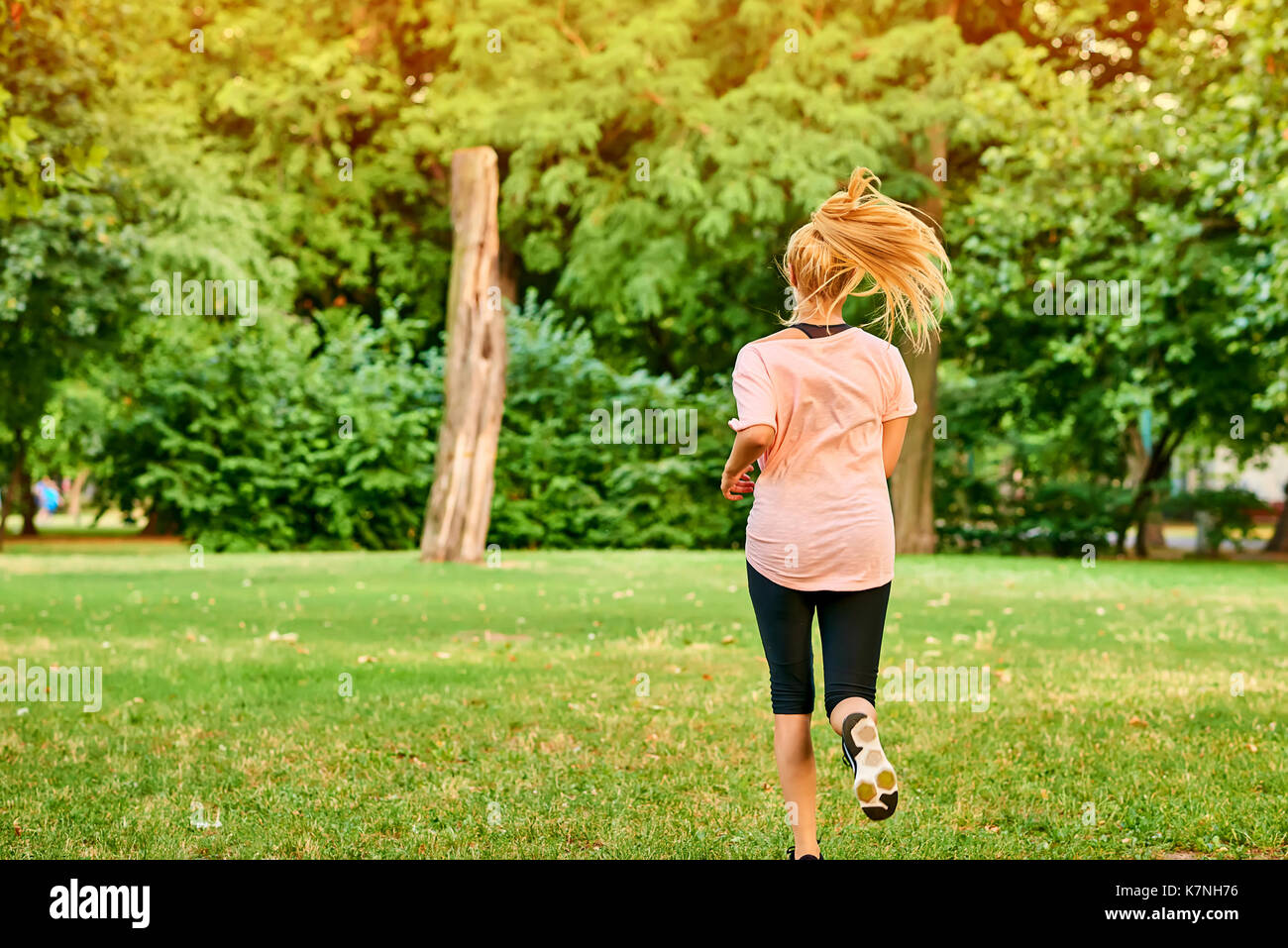 A beautiful young blond woman running away from the camera through a ...