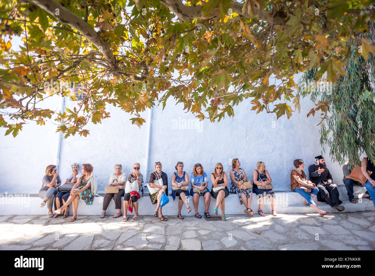 Ladies and a priest waiting outside a monastery in Tinos, Greece Stock ...