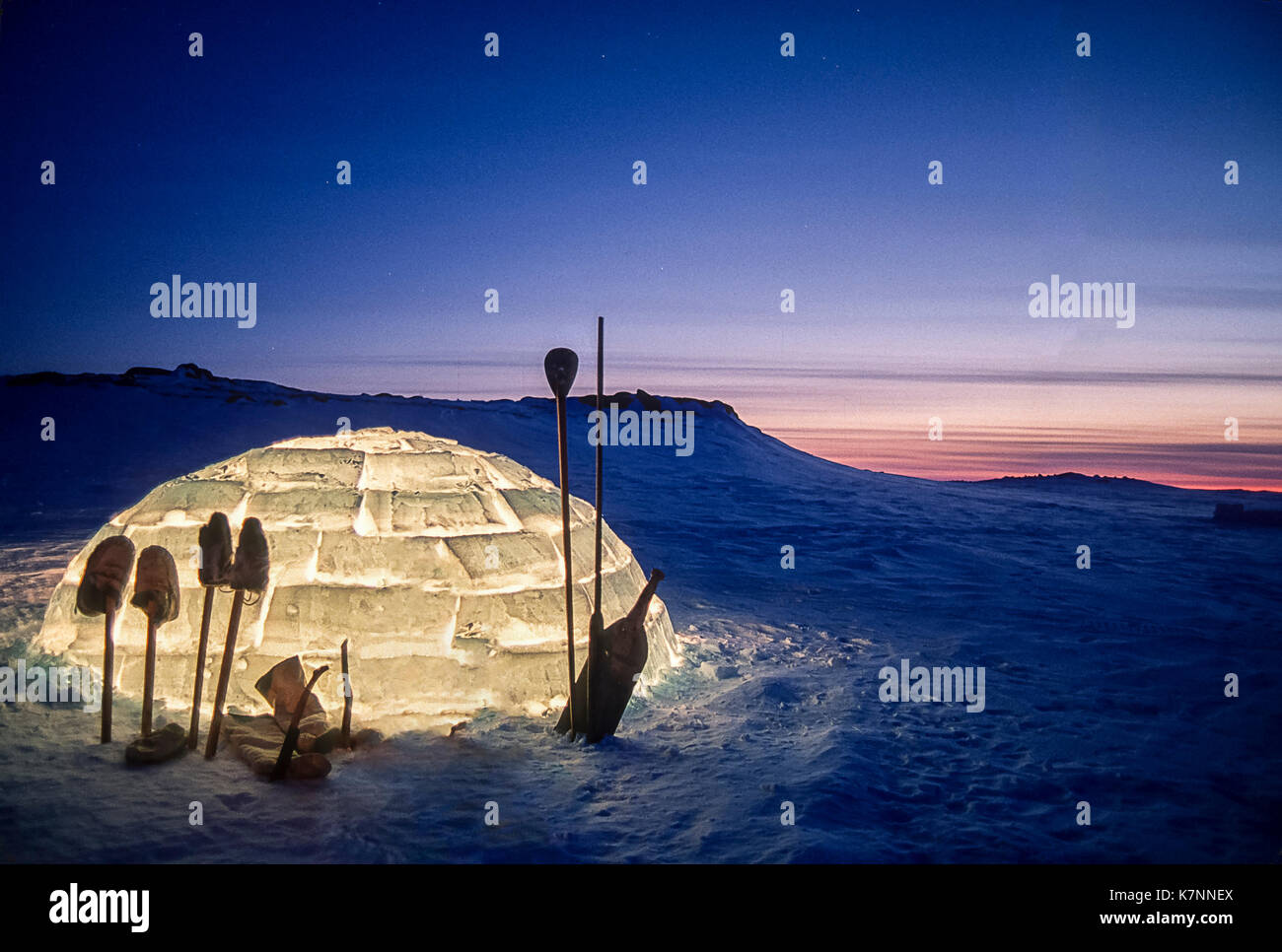 Inuit tools silhouetted against a lit igloo at dusk outside Baker Lake ...