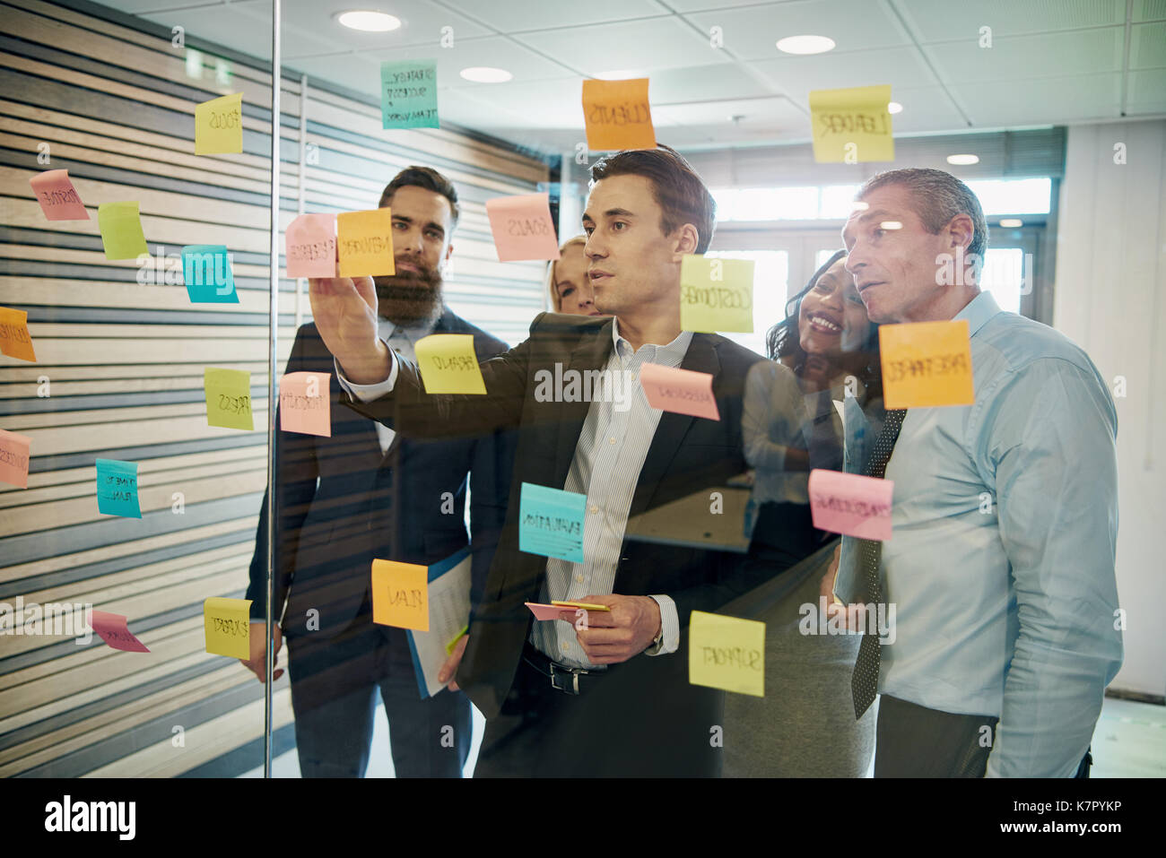 Group of business people brainstorming with sticky notes on glass ...
