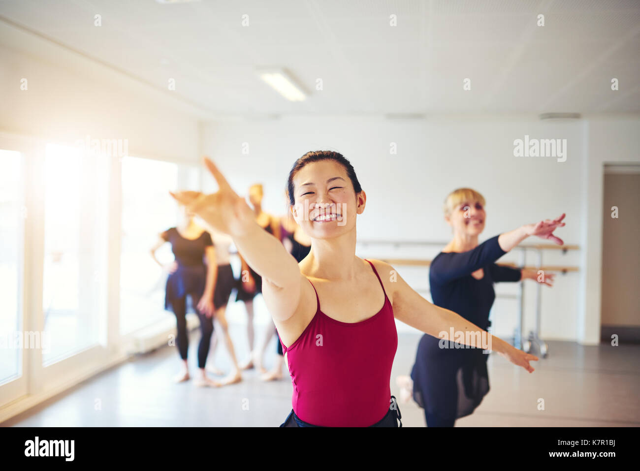 Smiling young Asian dance instructor leading a group of senior women ...