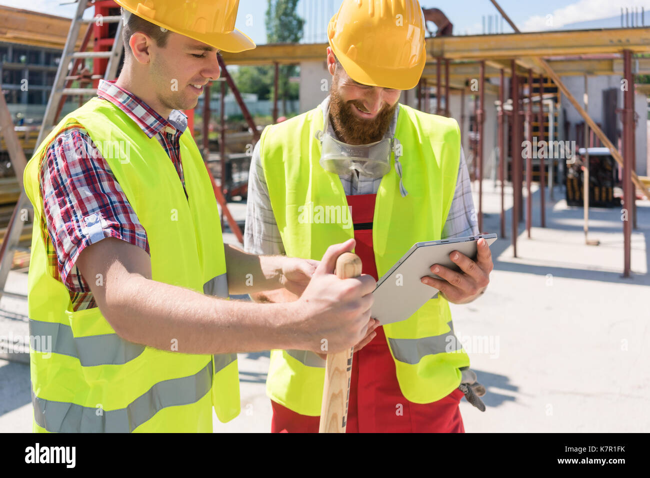 Two young construction workers smiling while using a tablet duri Stock ...