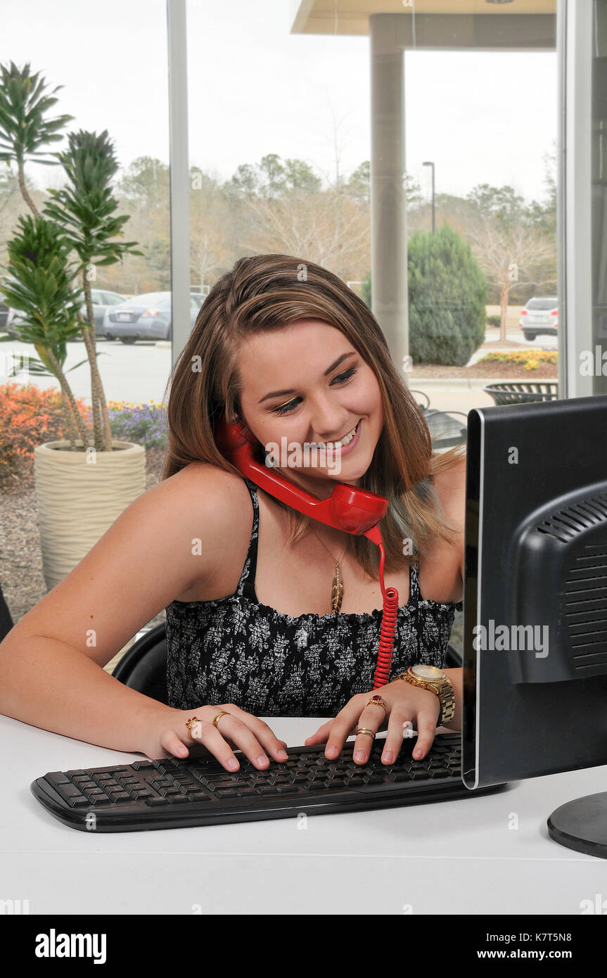 Woman executive or manager using a desktop computer and a landline ...