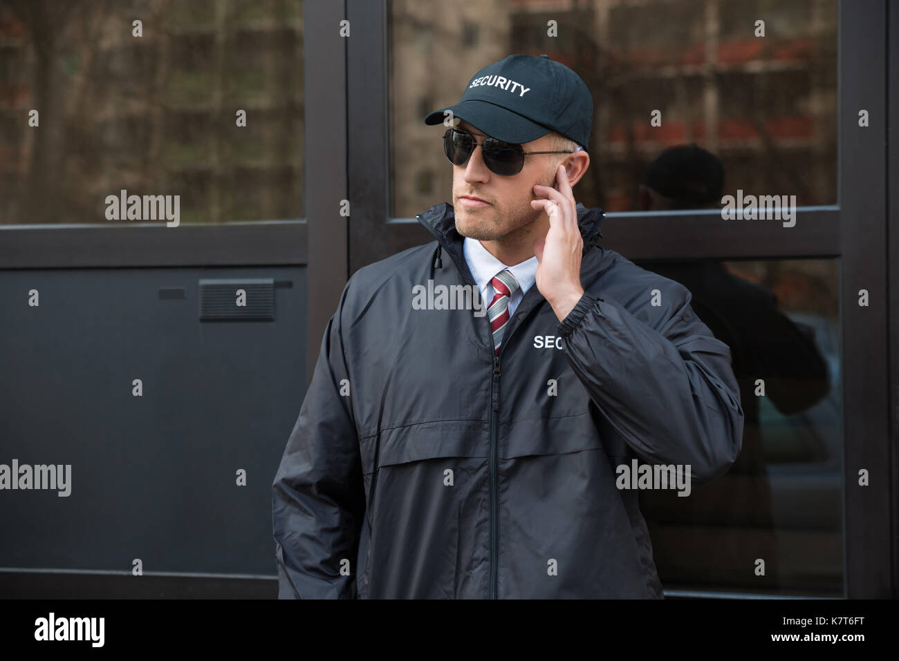 Young Security Guard Standing In Front Of The Glass Door Entrance Stock ...