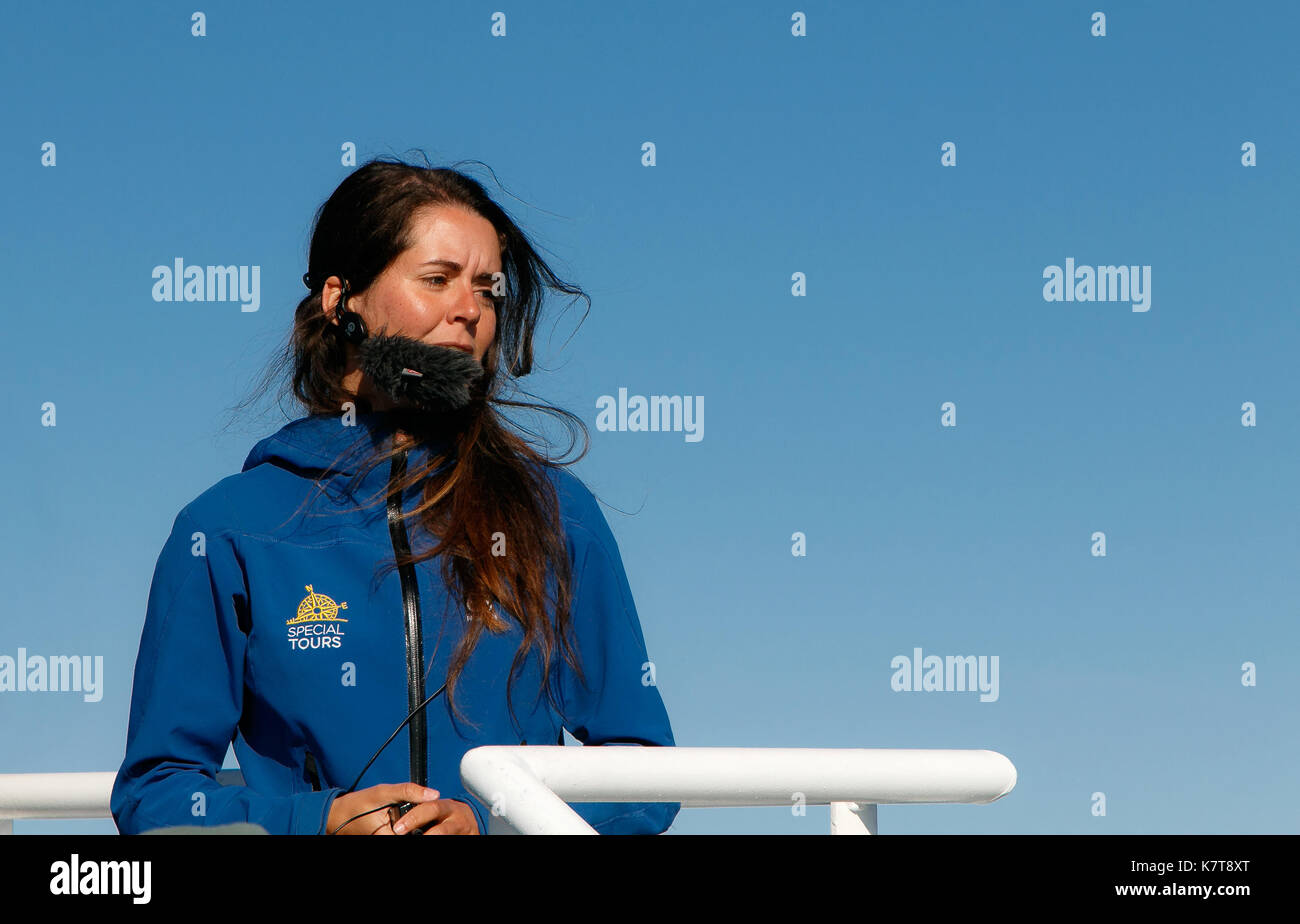 A female whale watching tour guide is speaking into her microphone ...