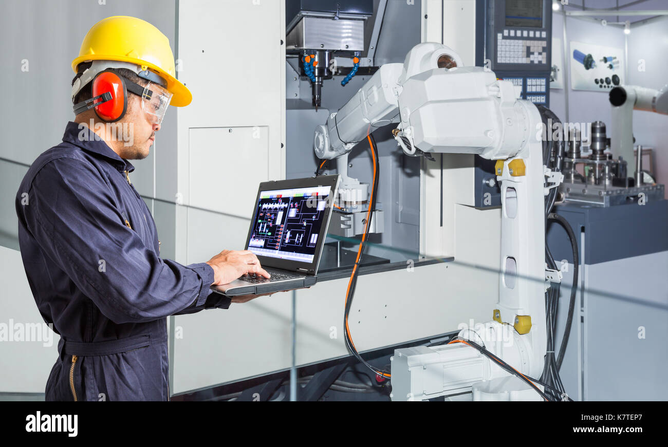 Engineer using laptop computer for maintenance automatic robotic hand machine tool in automotive ...